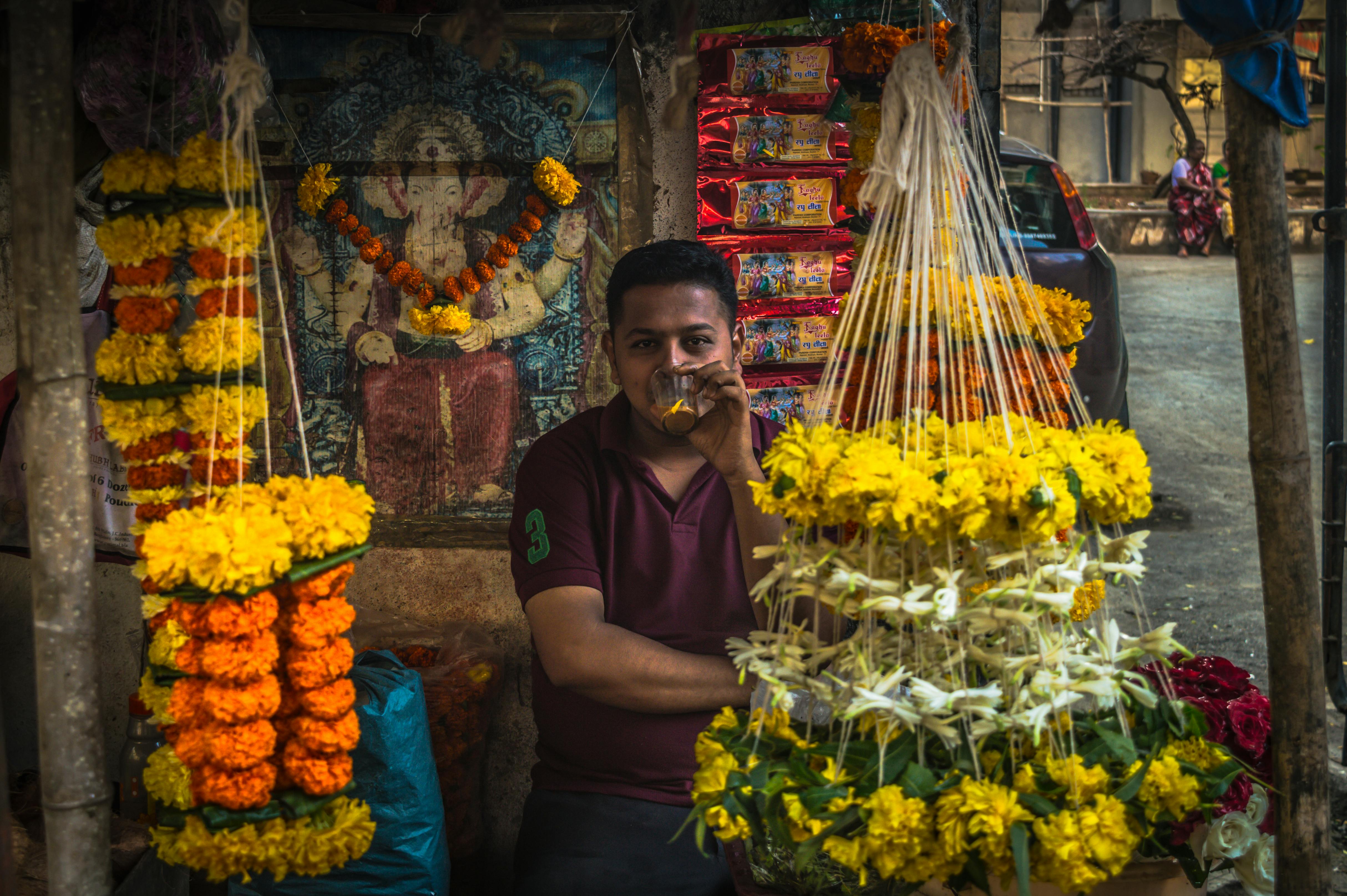 Street Flower Vendor with an Image of Ganesha Behind His Back · Free ...