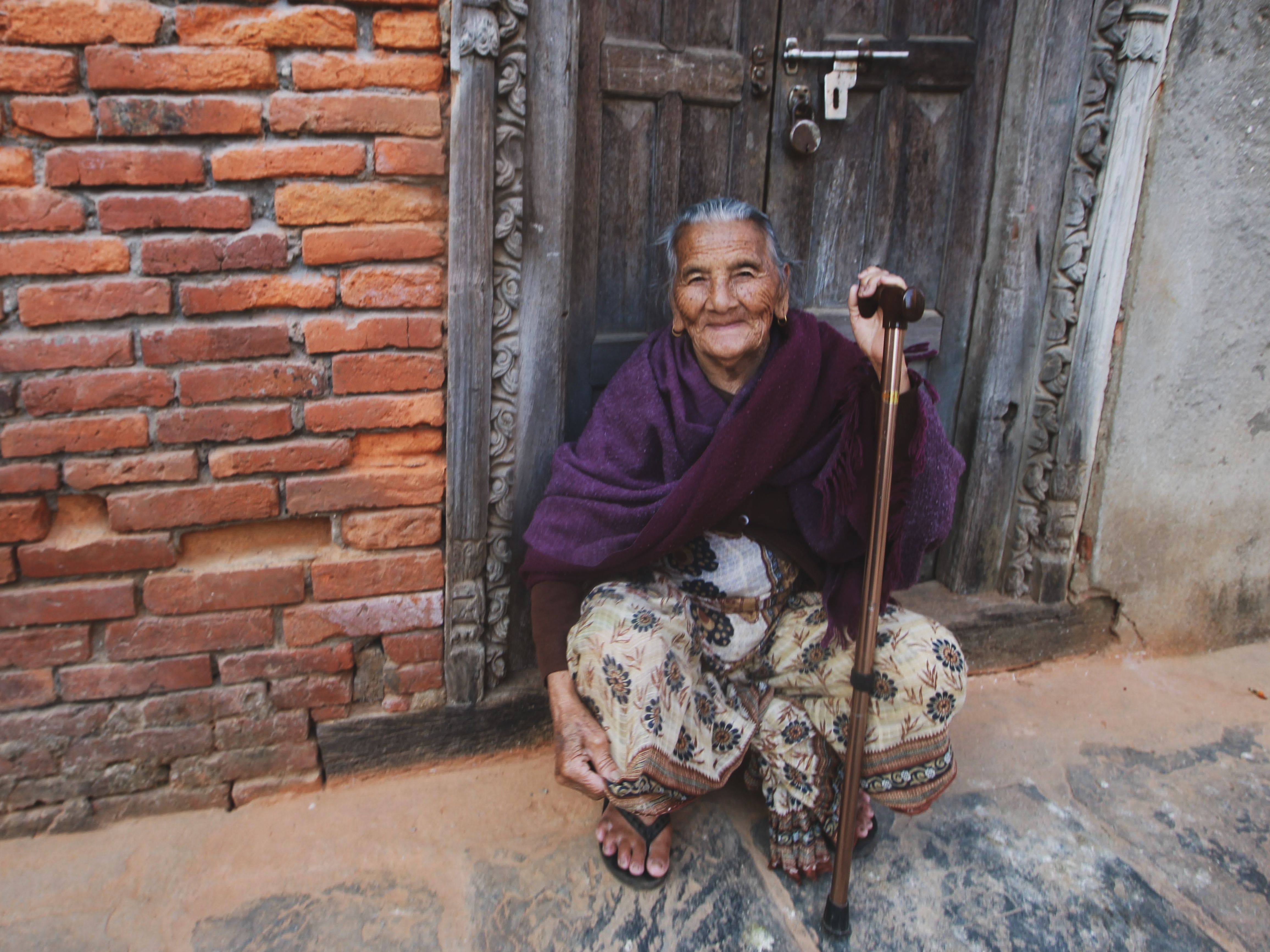 Elderly Woman Crouching by Entrance Doors · Free Stock Photo