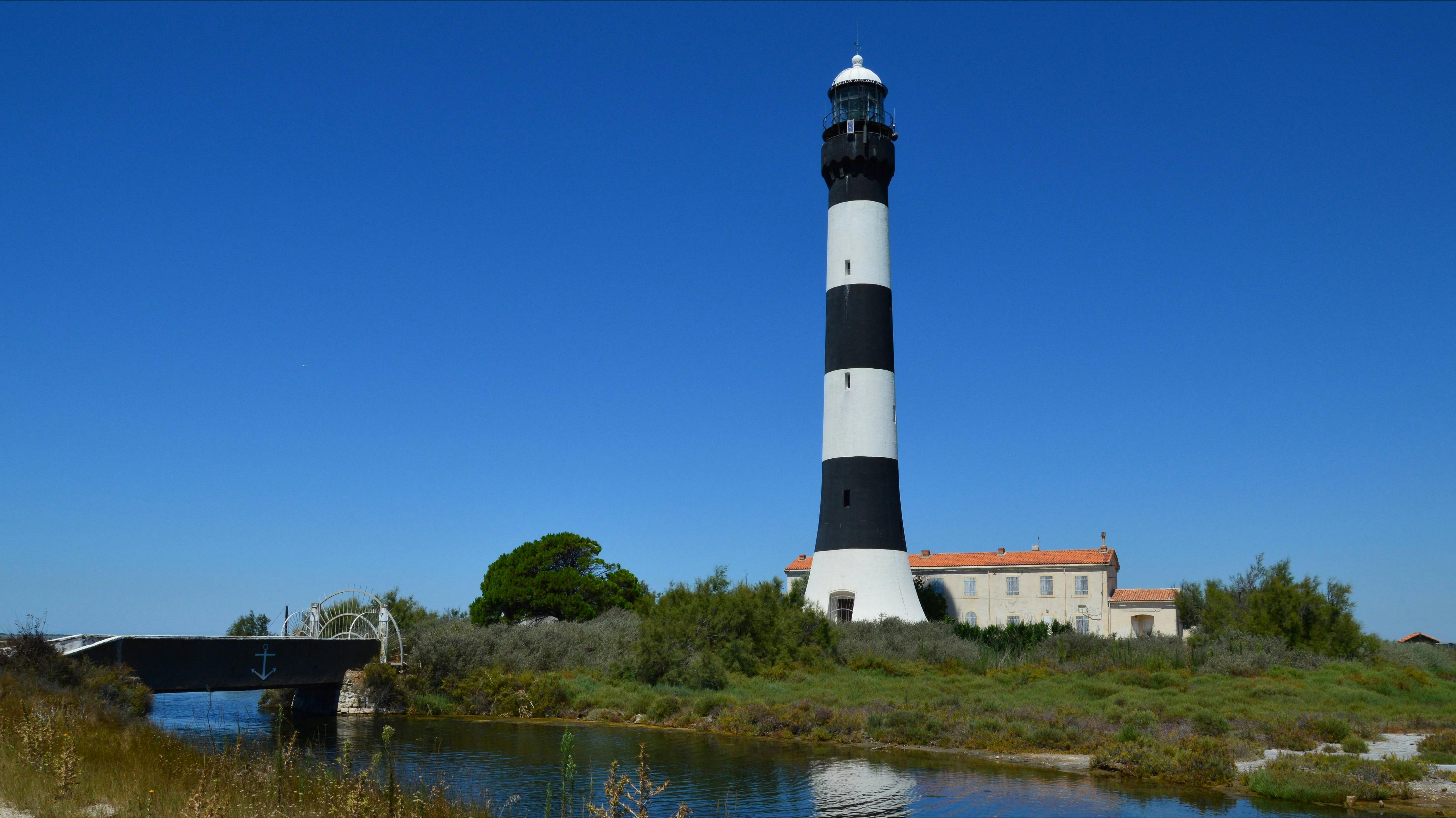 Lighthouse on Shore against Blue Sky · Free Stock Photo