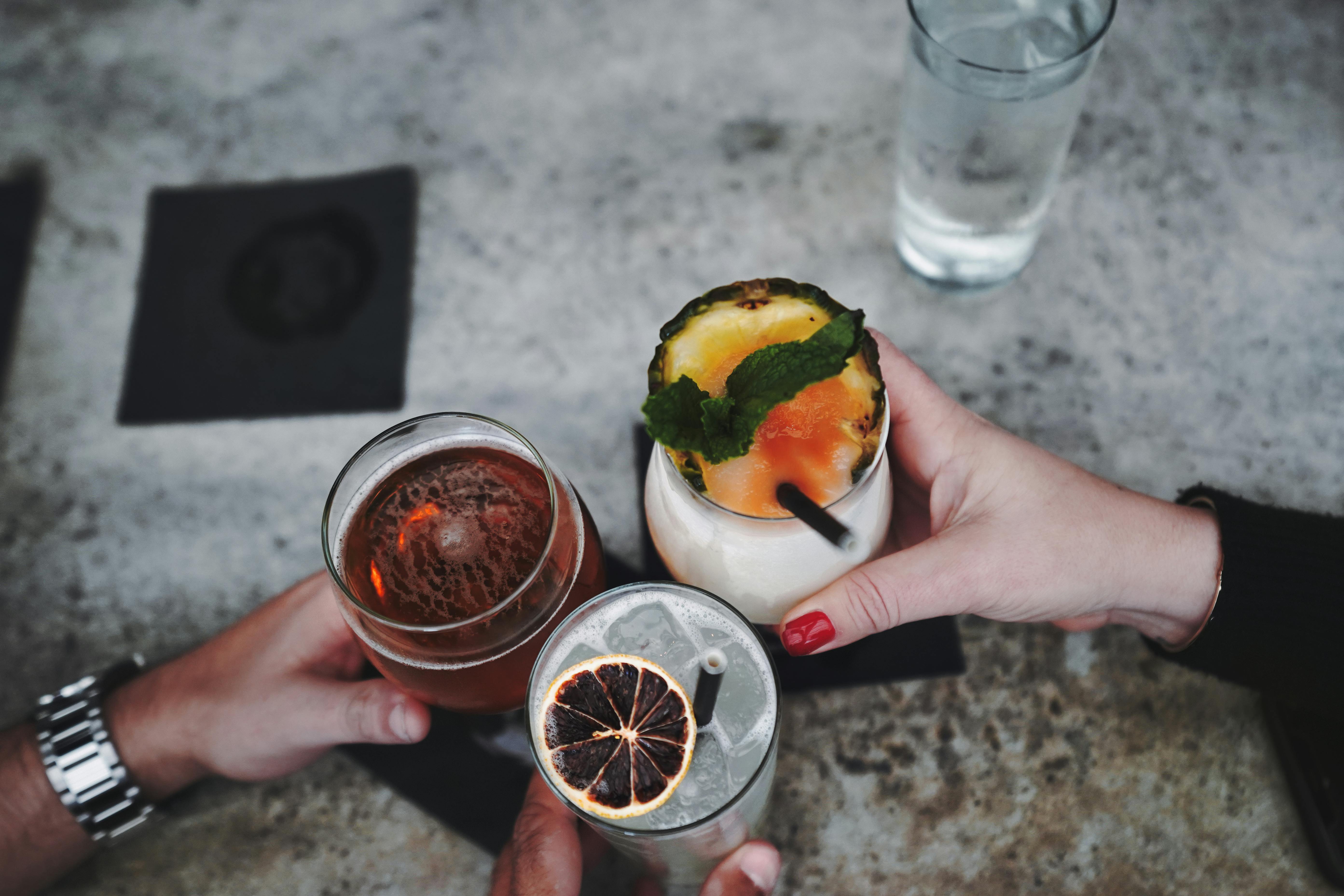 Photo of Hands Holding Alcoholic Drinks · Free Stock Photo