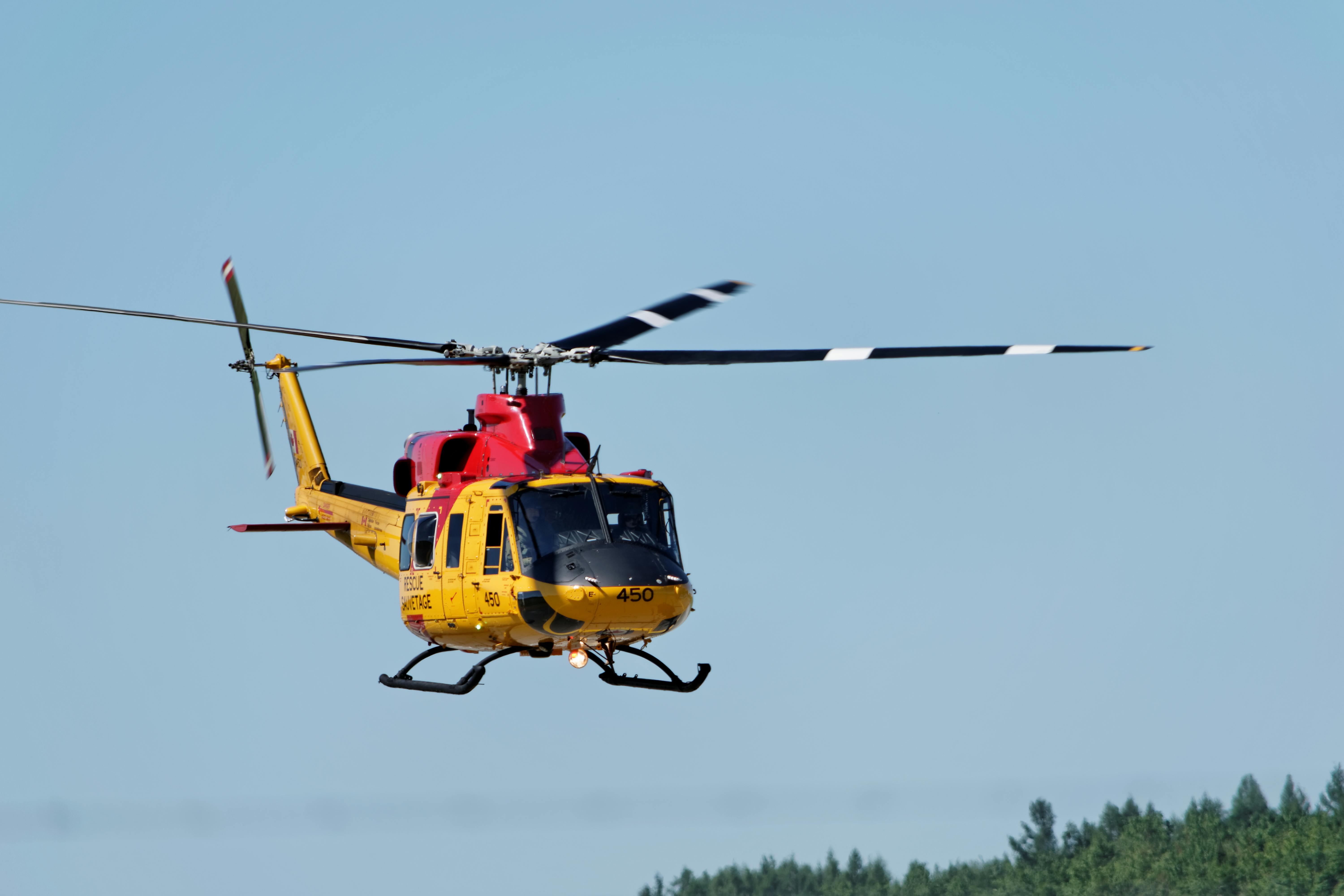 A Yellow and Red Helicopter Flying Under the Blue Sky · Free Stock Photo