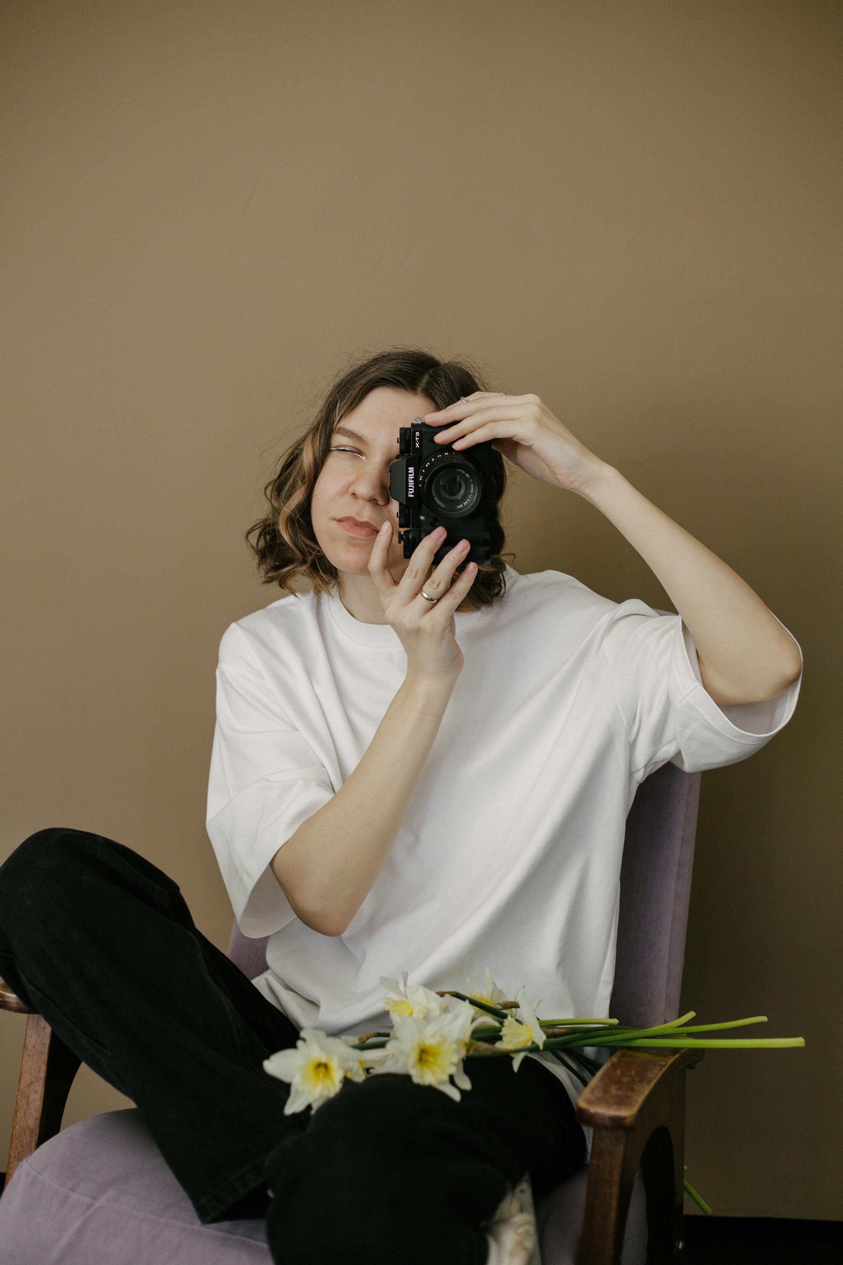 Woman Taking a Photo While Sitting on Chair · Free Stock Photo
