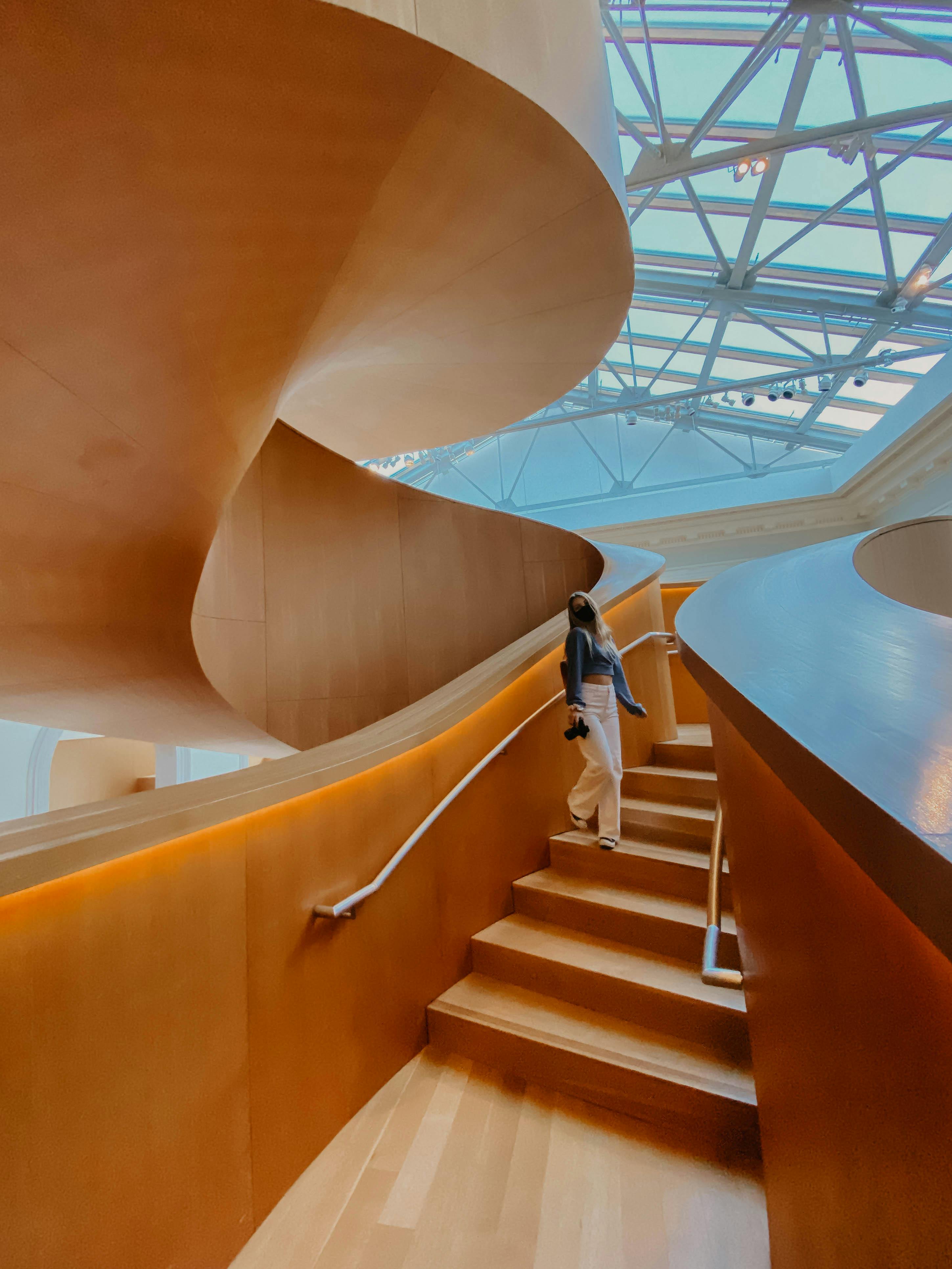 Woman in White Shirt and Blue Denim Jeans Walking Down on Brown Spiral ...
