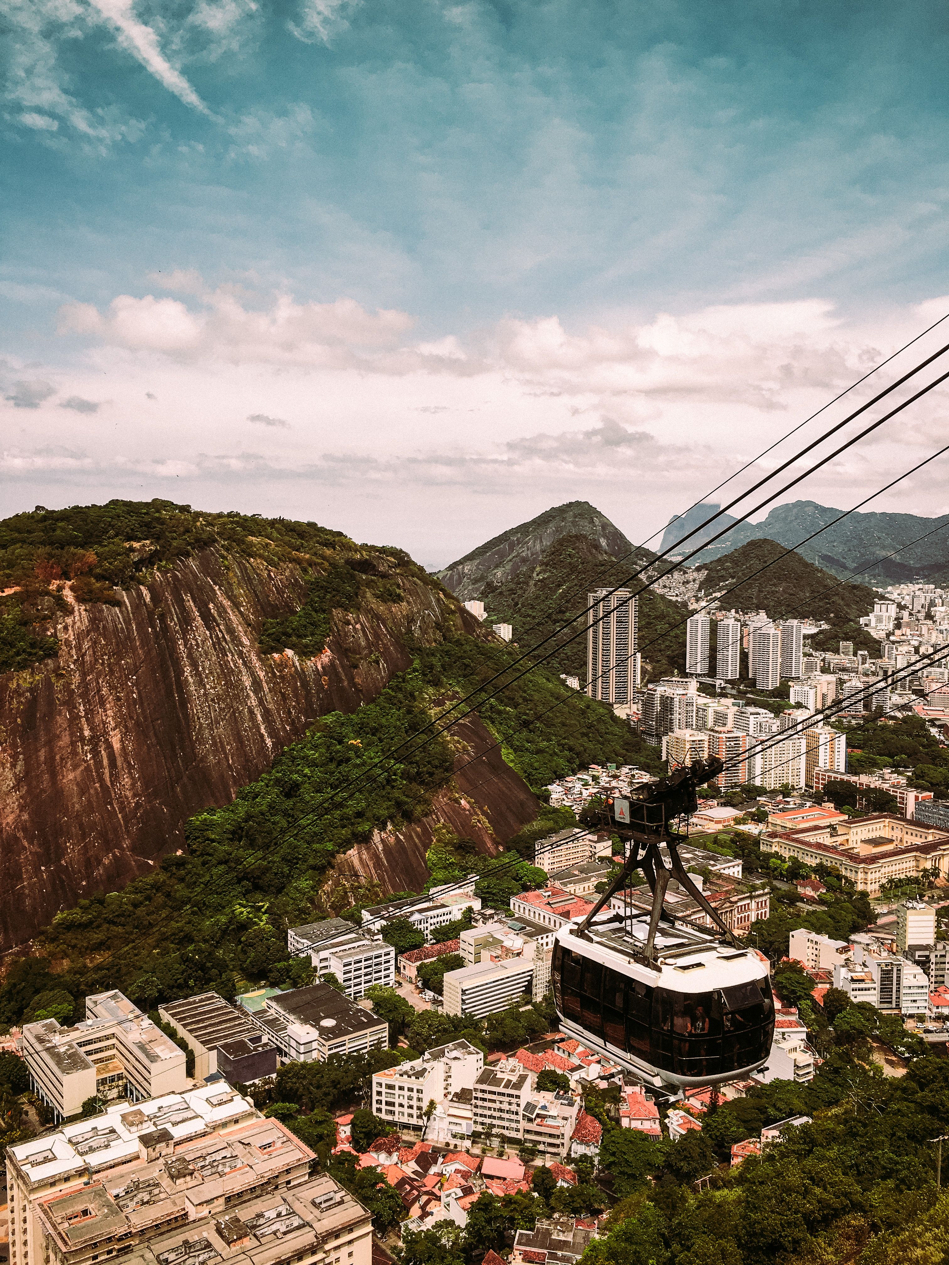 A Cable Car Over City Buildings Near Mountains · Free Stock Photo