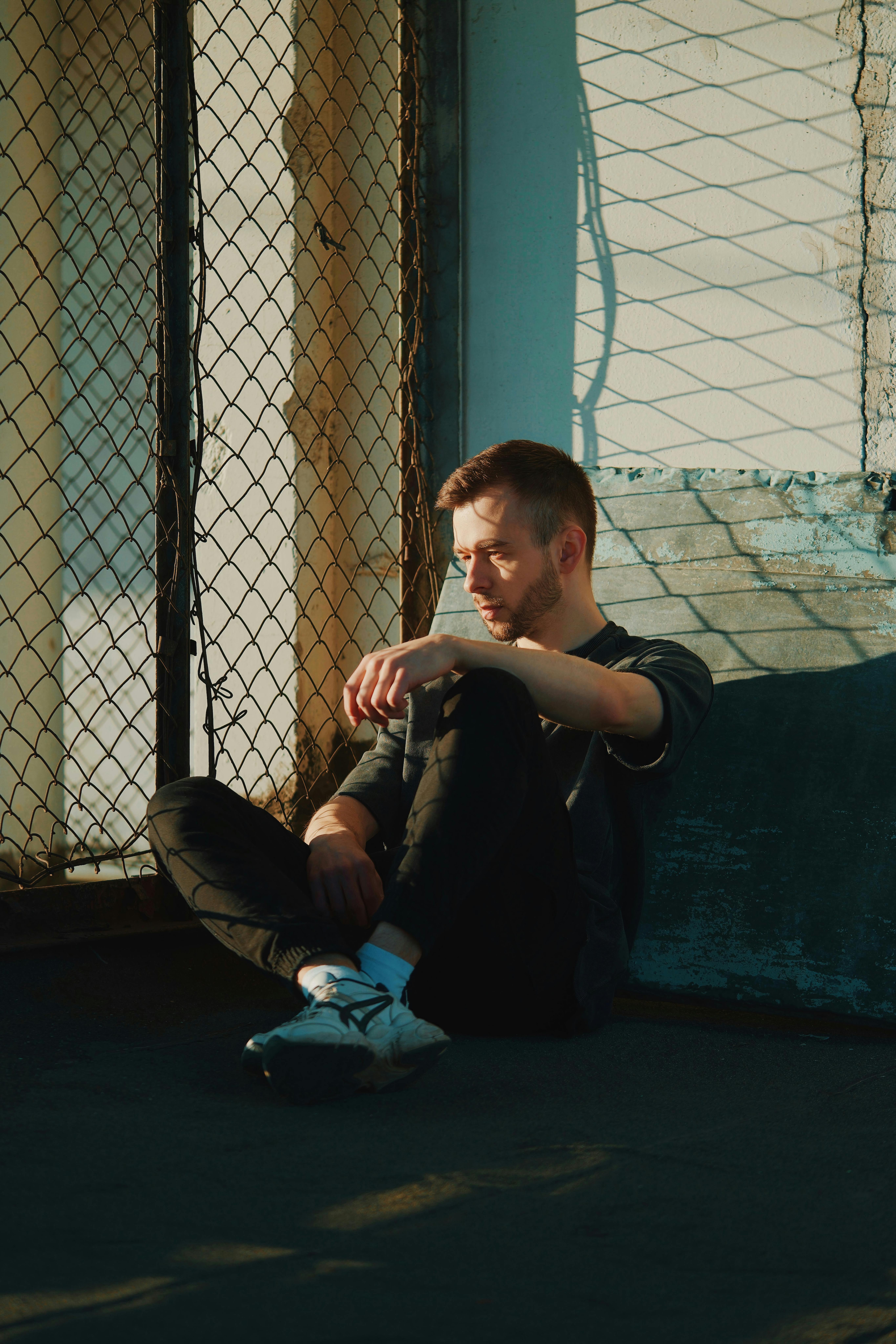 A Man Sitting Next to a Fence · Free Stock Photo