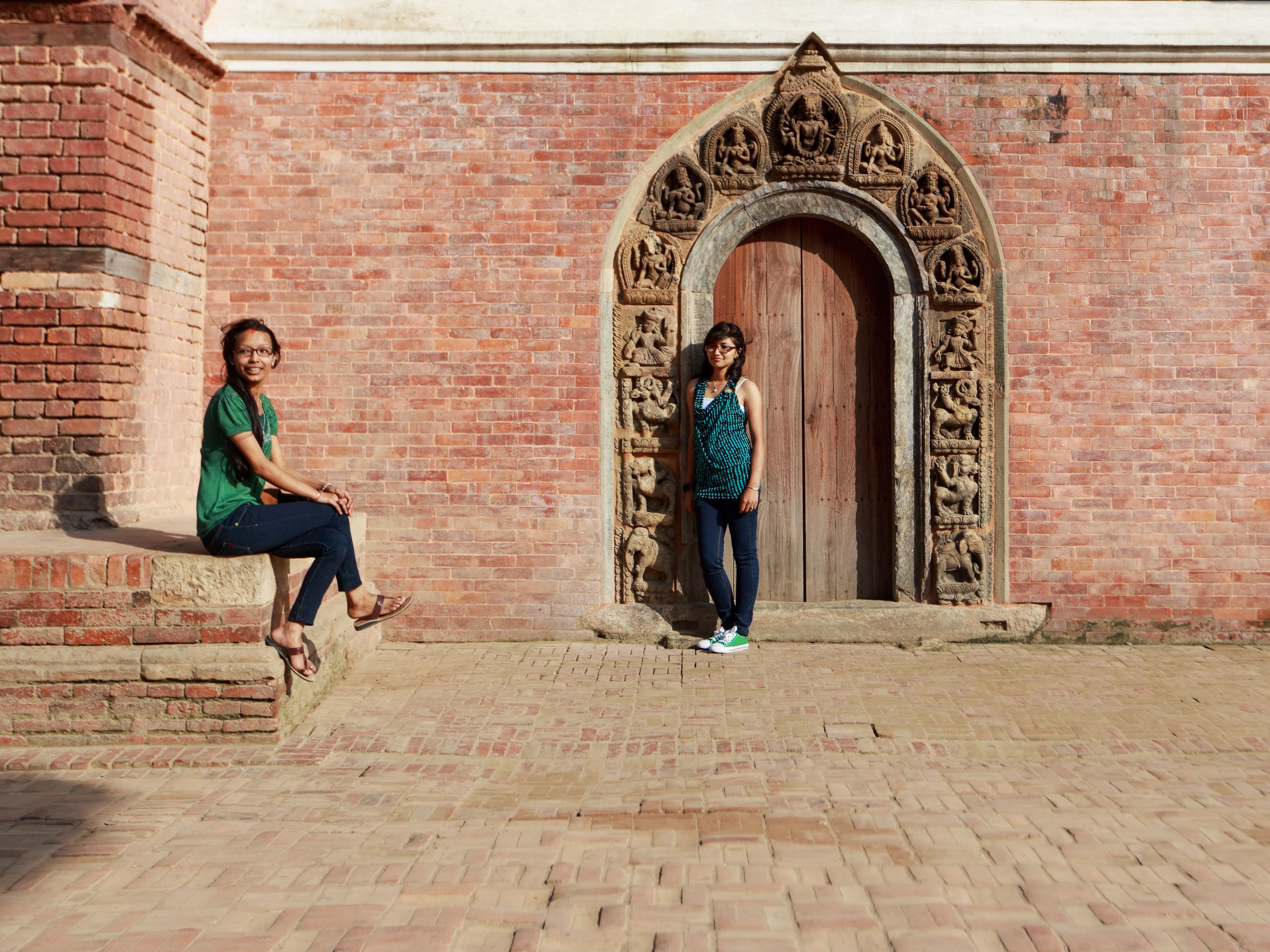 Two Women Near a Brick Wall · Free Stock Photo