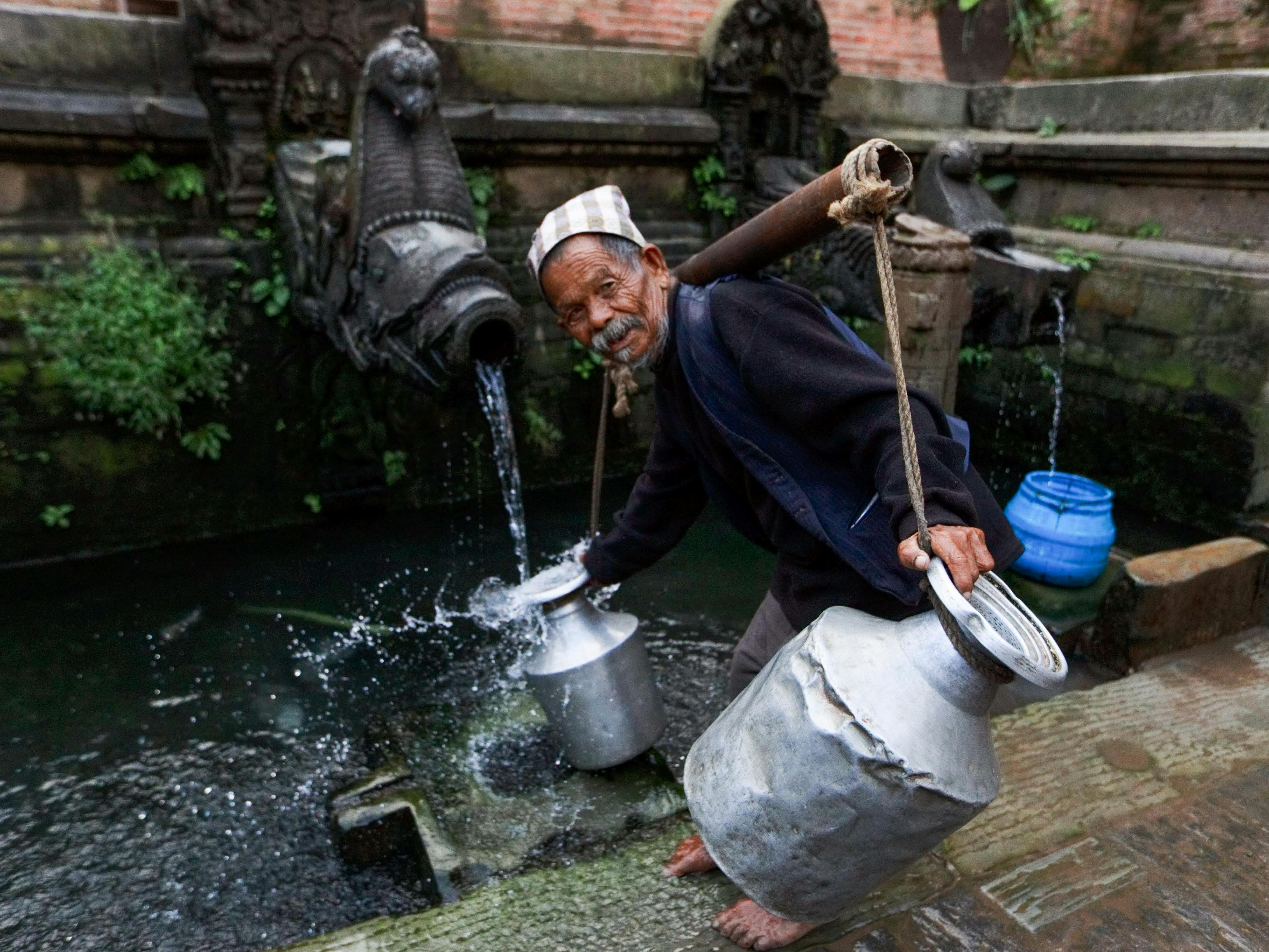 Elderly Man fetching Water using Metals Jars · Free Stock Photo