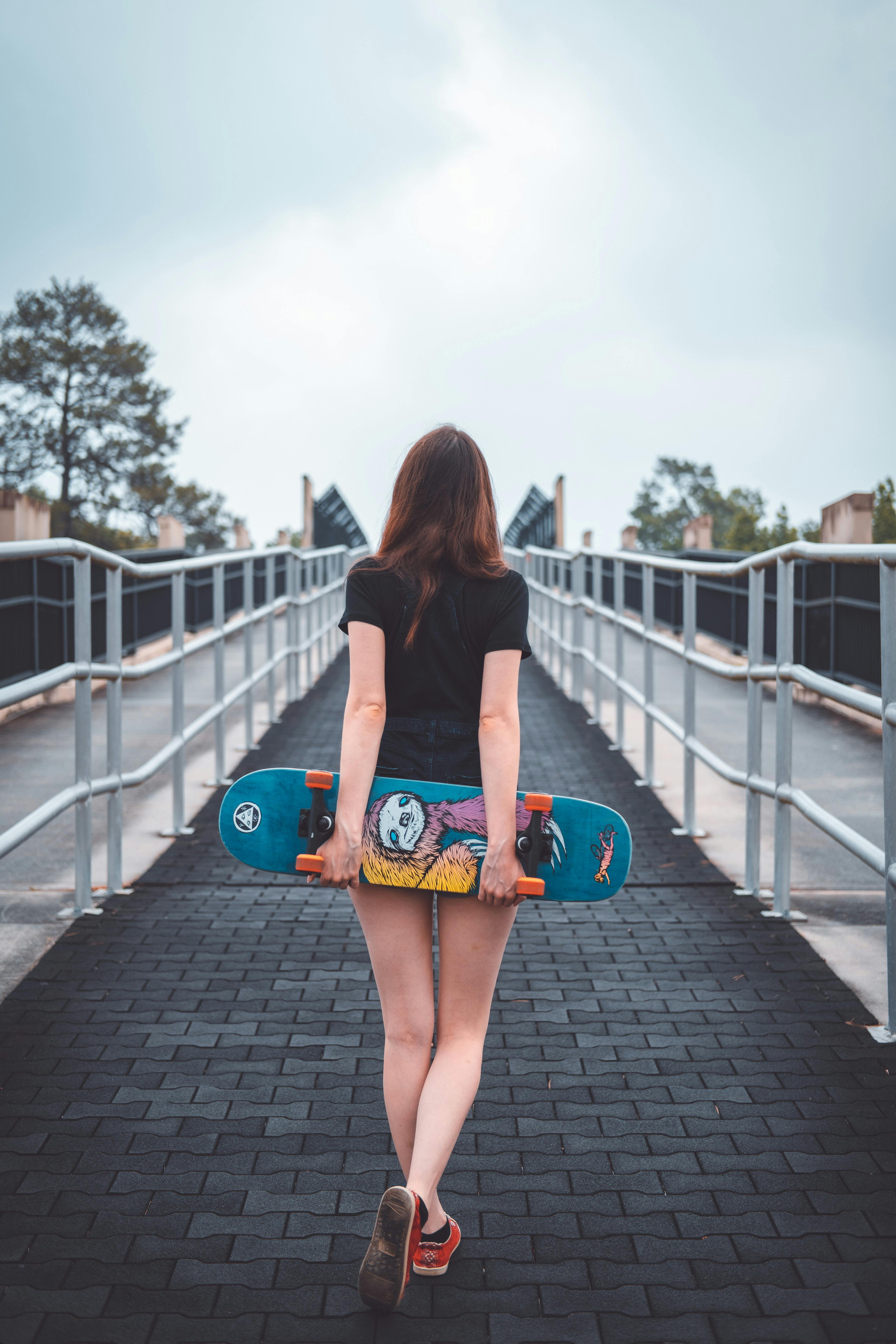 Back View of a Person Holding a Skateboard · Free Stock Photo
