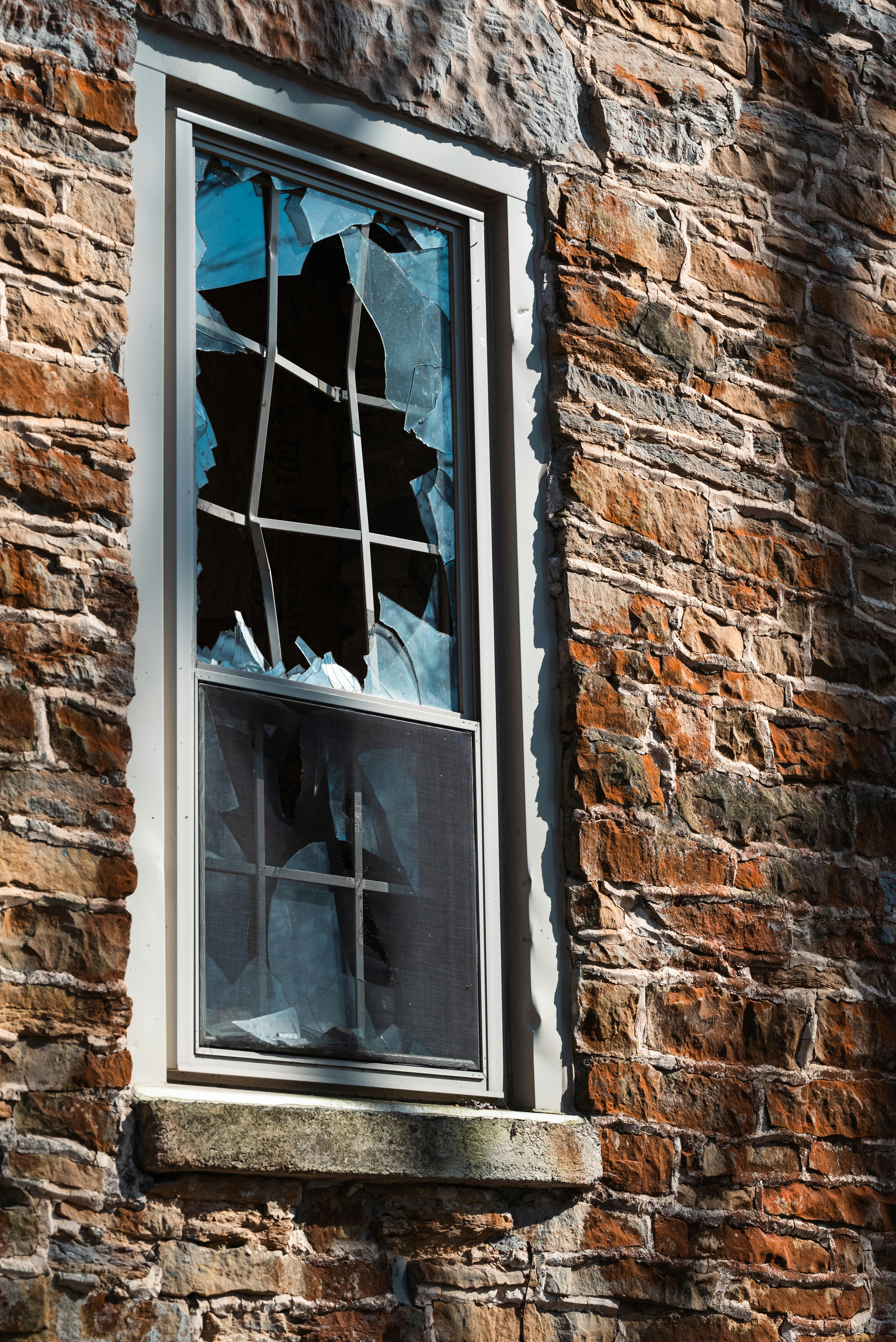 A Broken Glass Window on a Brown Brick Wall · Free Stock Photo