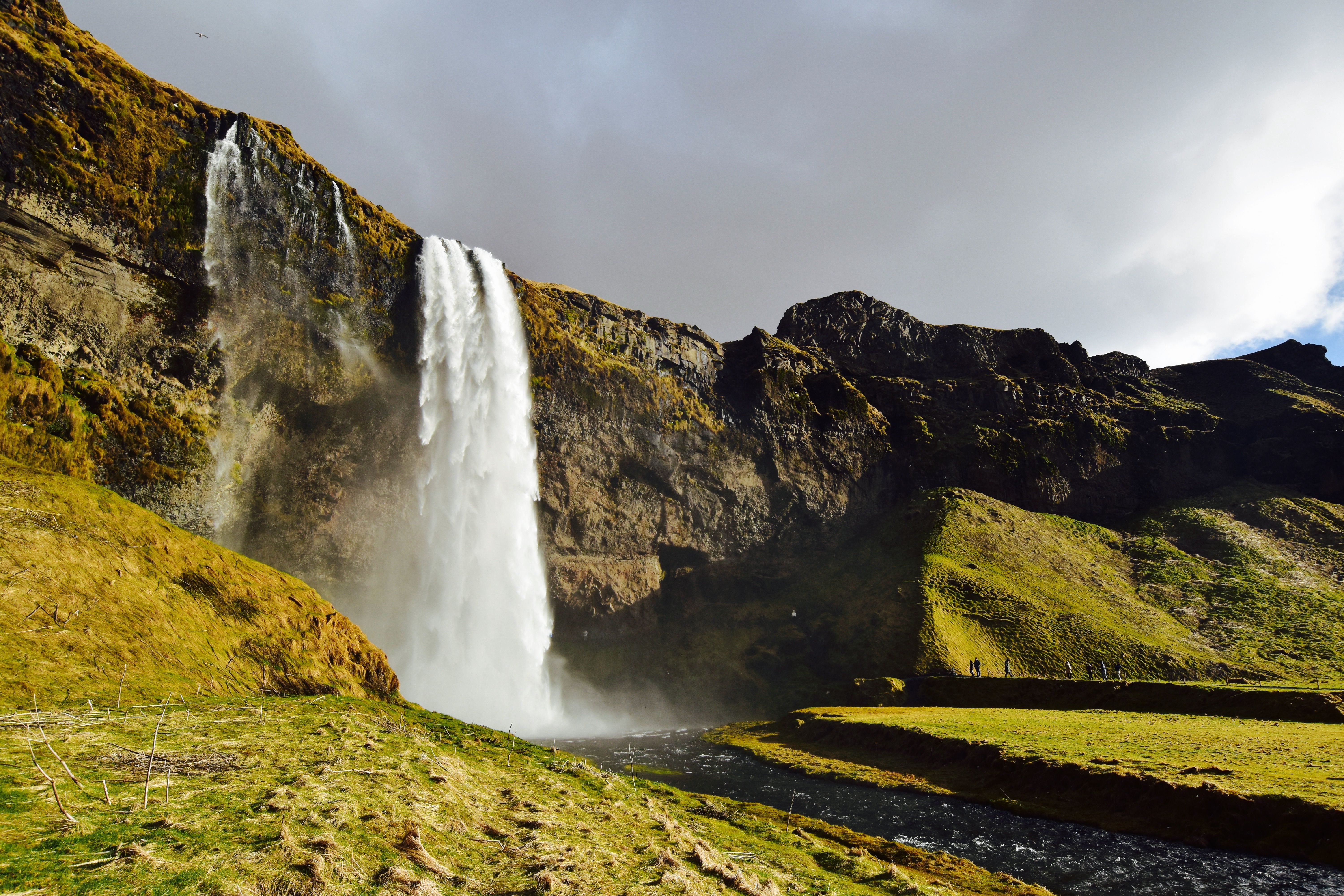 Waterfalls on Green Grass Field Under Gloomy Sky · Free Stock Photo