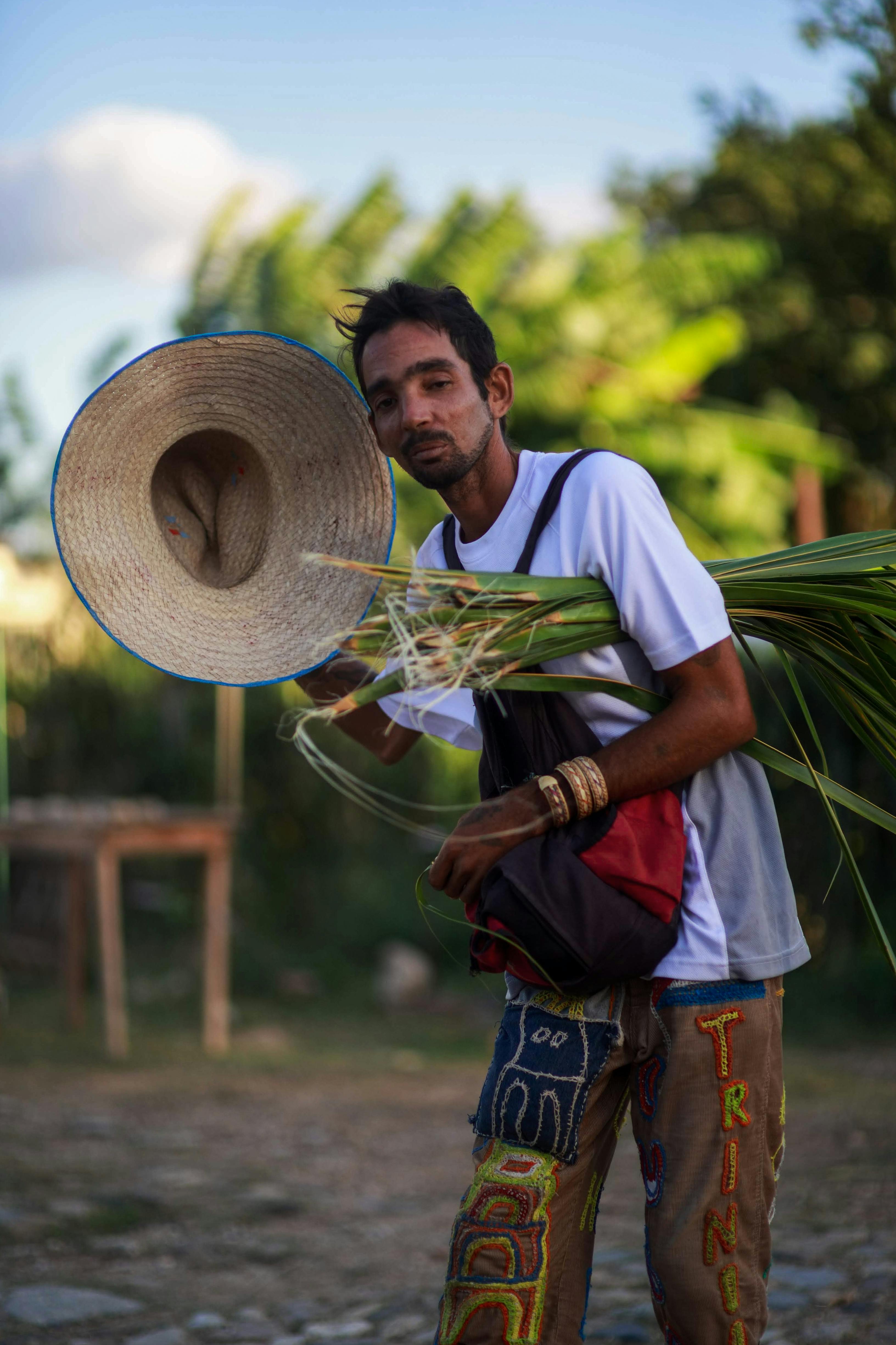 A Man Holding a Bunch of Green Leaves and Brown Hat · Free Stock Photo