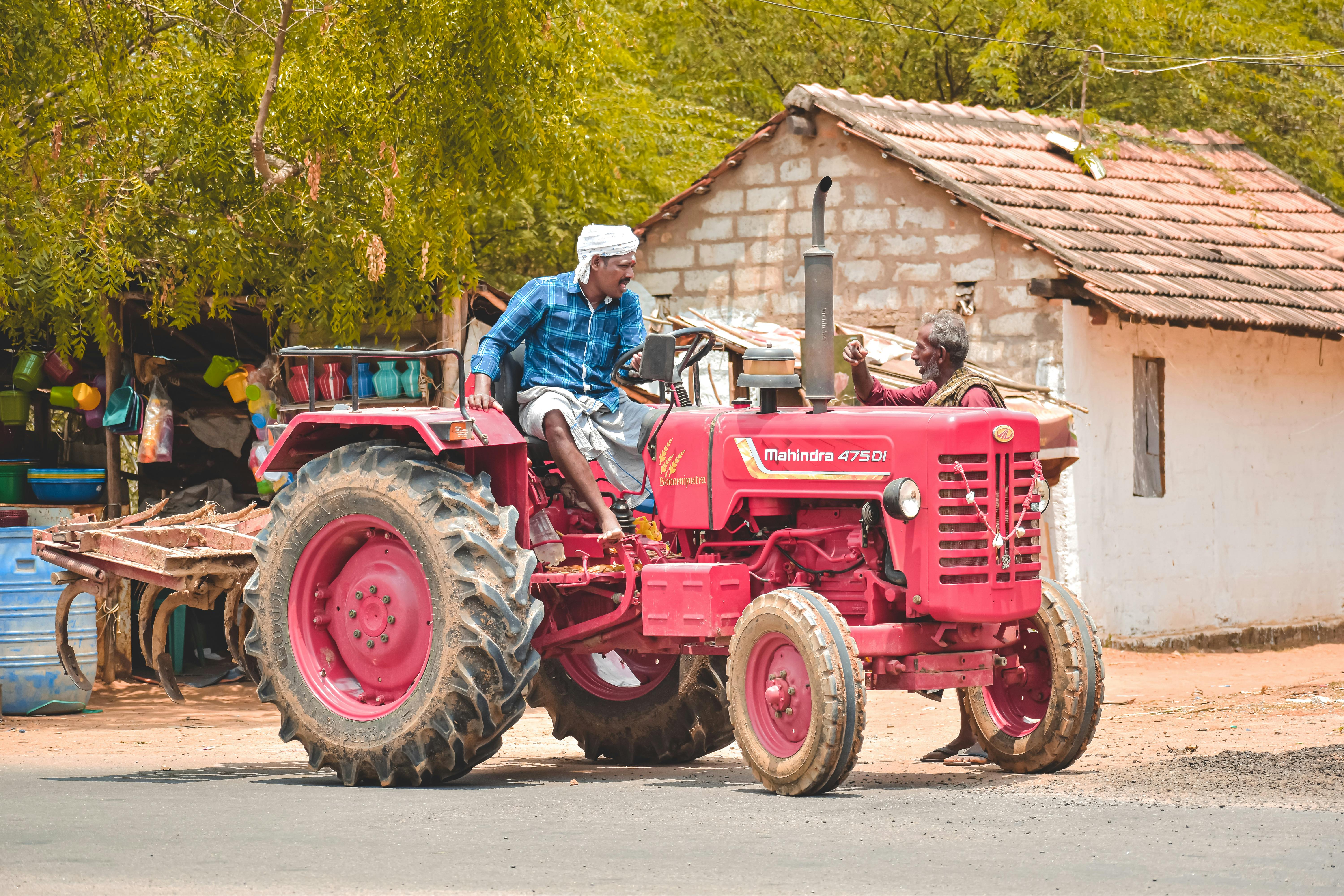 A Man Sitting on a Red Tractor · Free Stock Photo