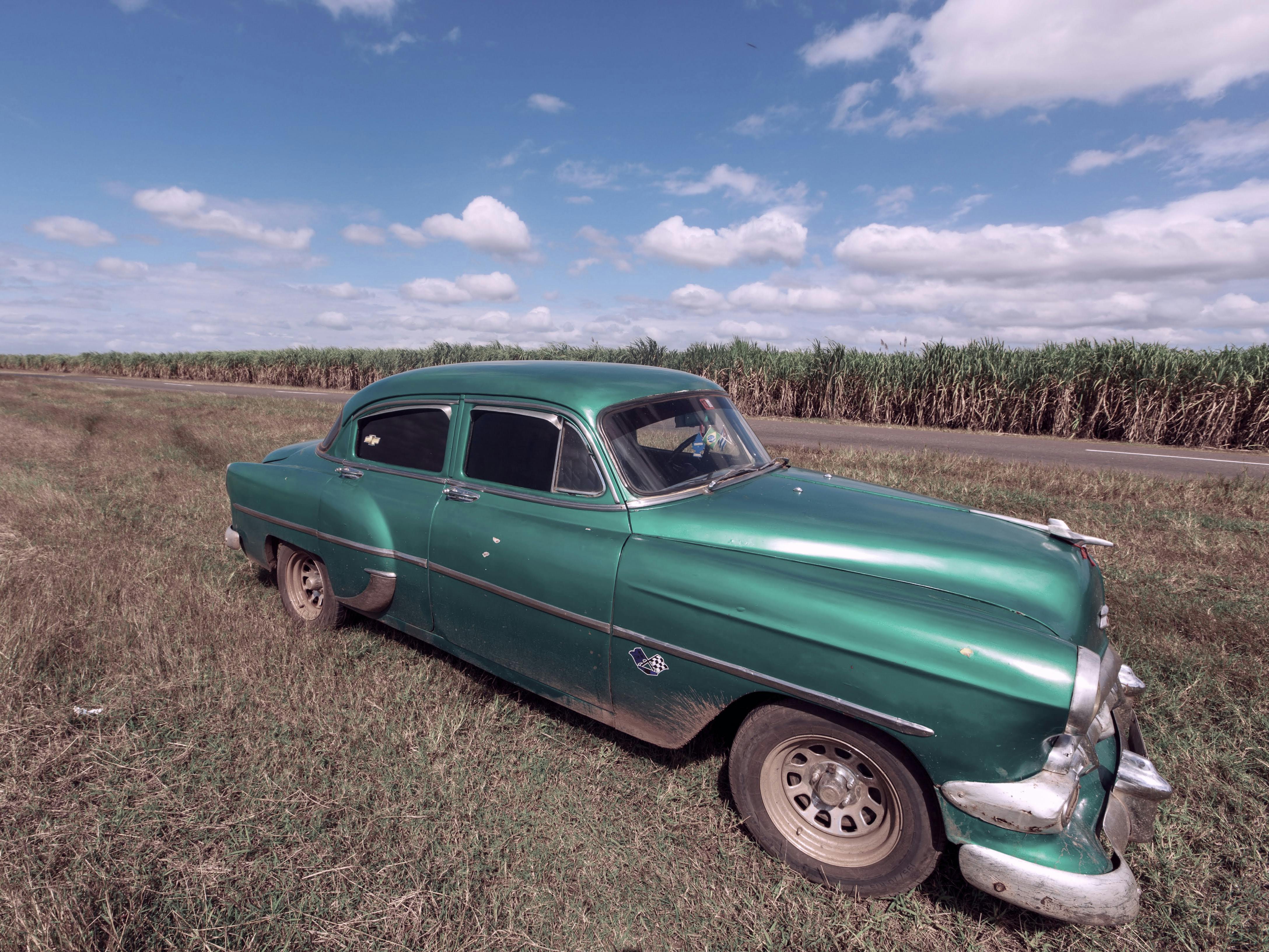 A Green Vintage Car Parked on Brown Grass Field · Free Stock Photo