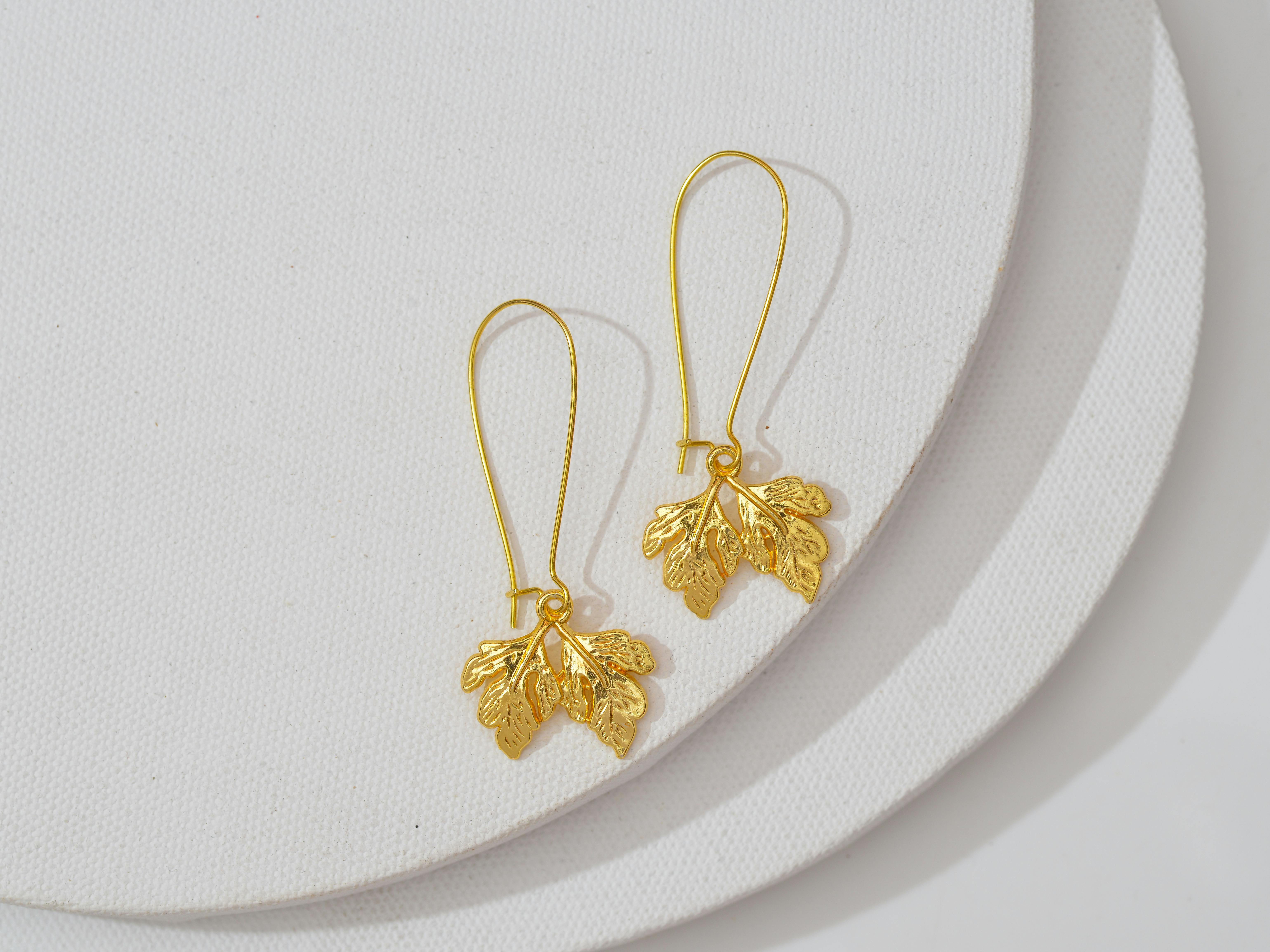 Gold Leaf Shape Earrings on White Background · Free Stock Photo