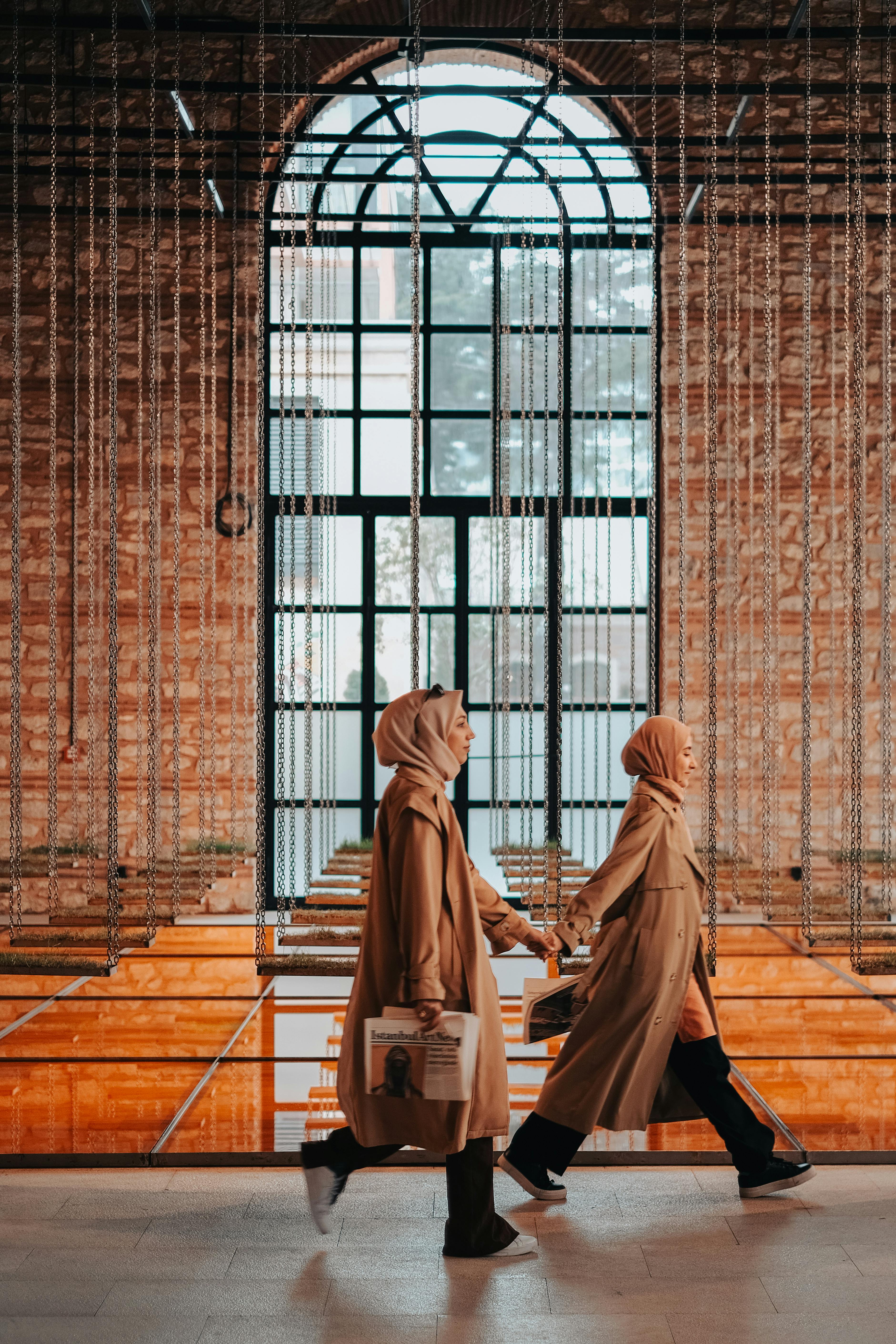 Women Walking Past Swings in Building · Free Stock Photo