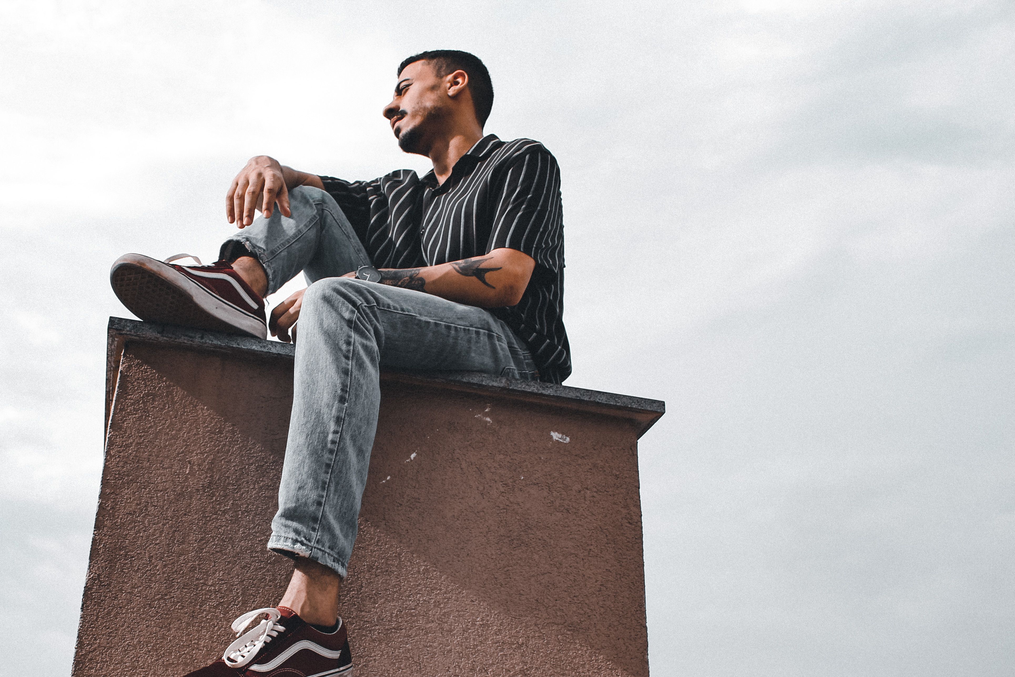 Man Sitting on Column against Blue Sky · Free Stock Photo