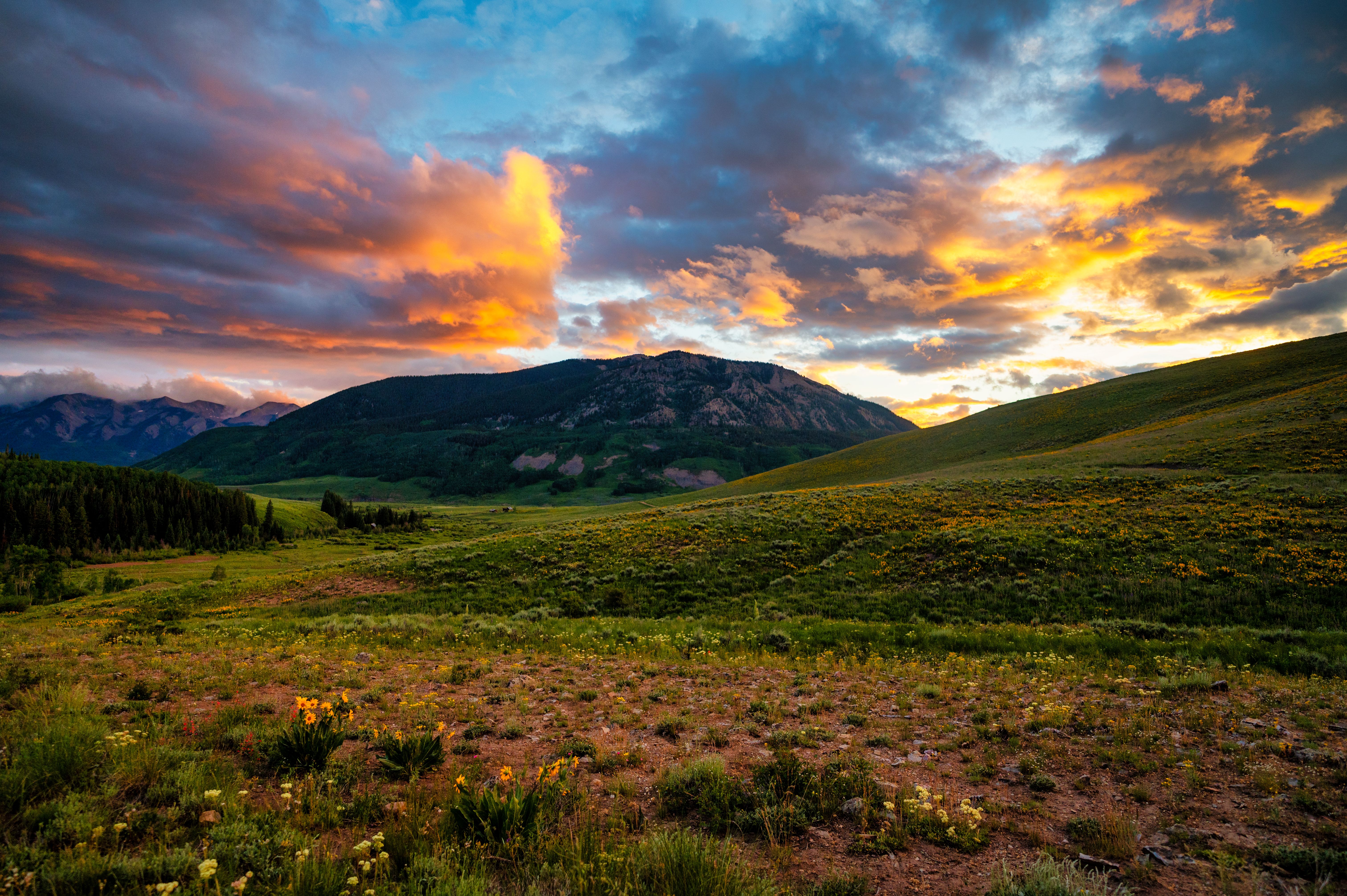 Green Grass Field Near Mountain Under Cloudy Sky · Free Stock Photo
