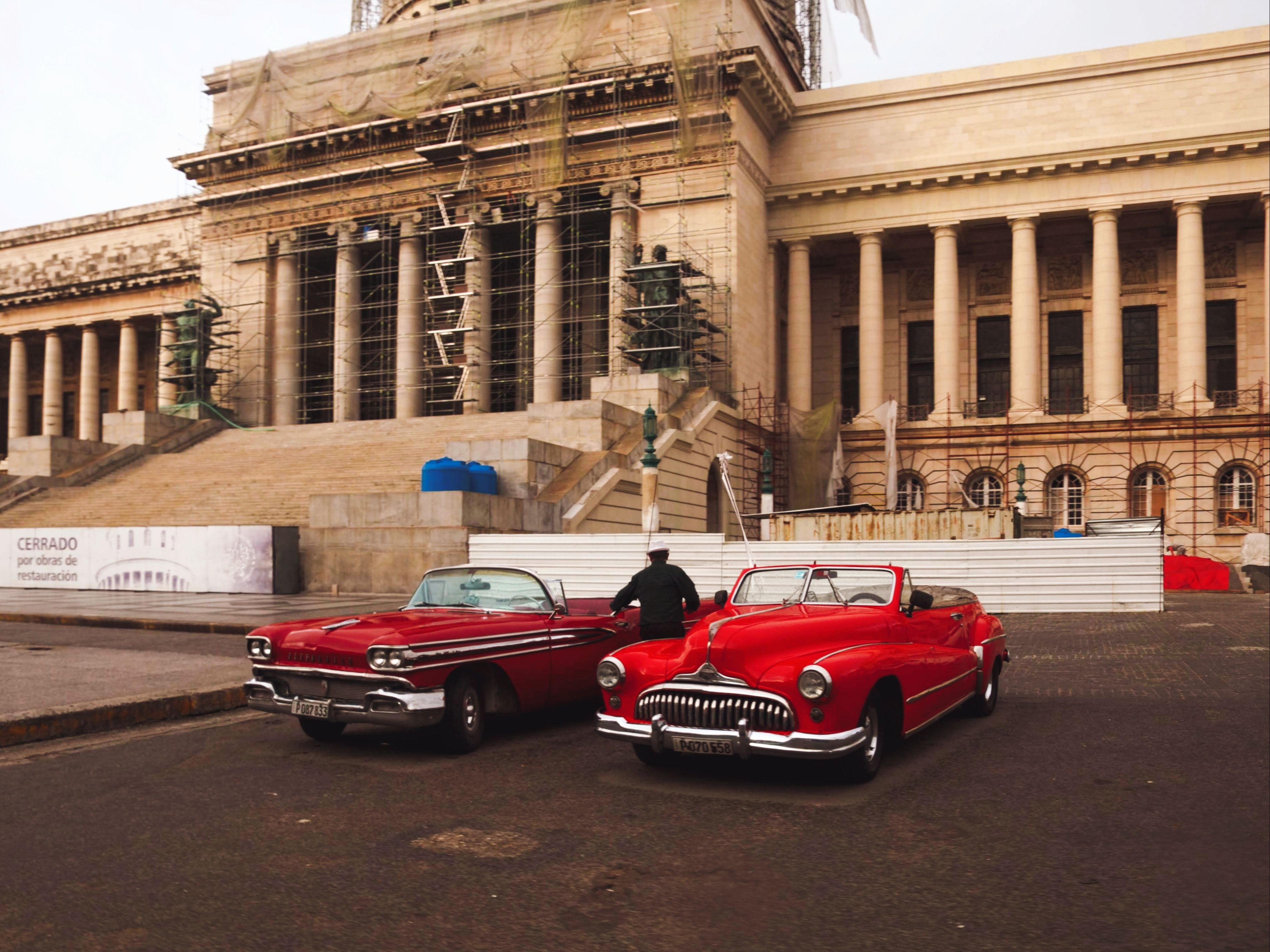 Red Classic Cars Parked Near Brown Concrete Building · Free Stock Photo
