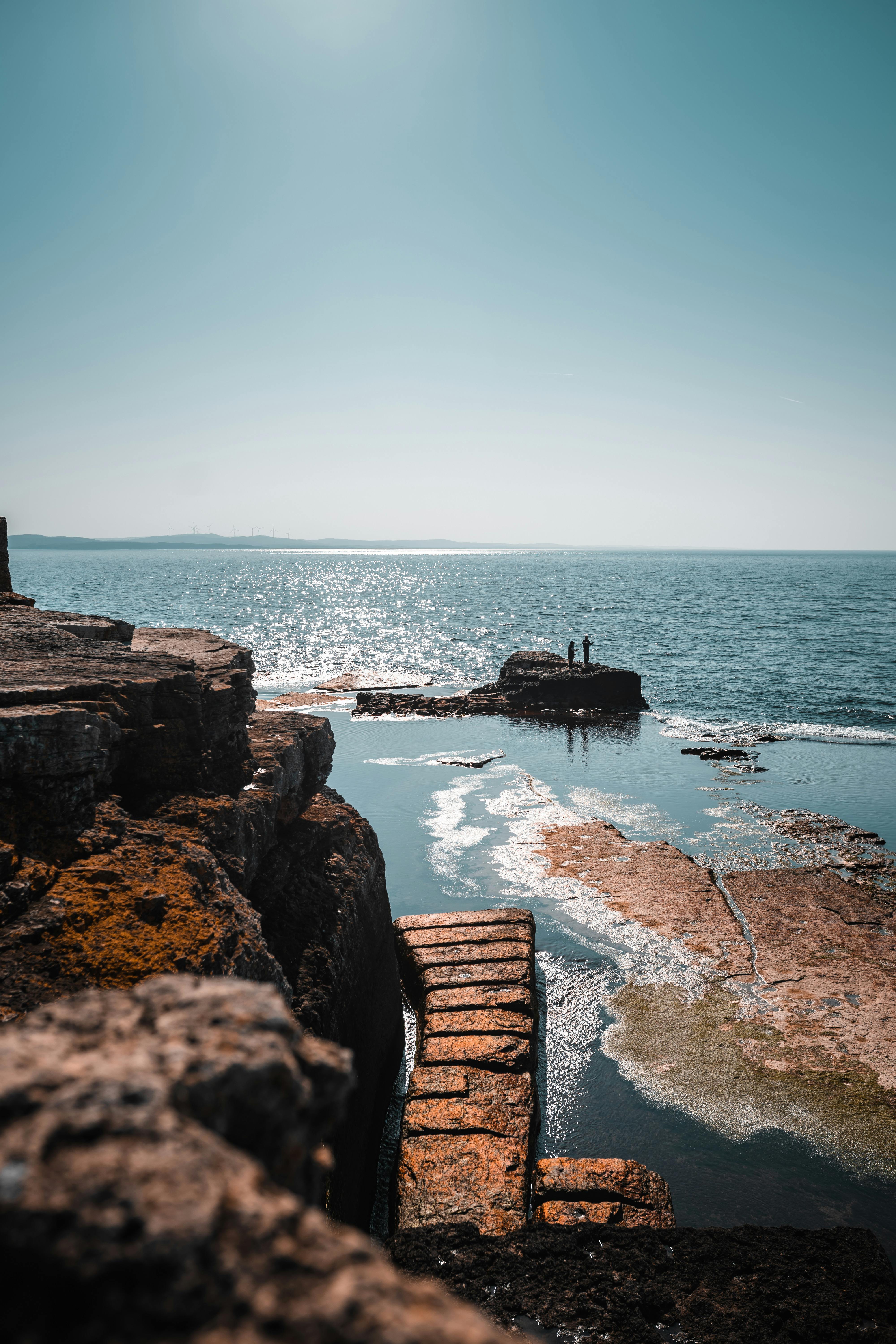 People Standing on Rock Formation on Seaside · Free Stock Photo