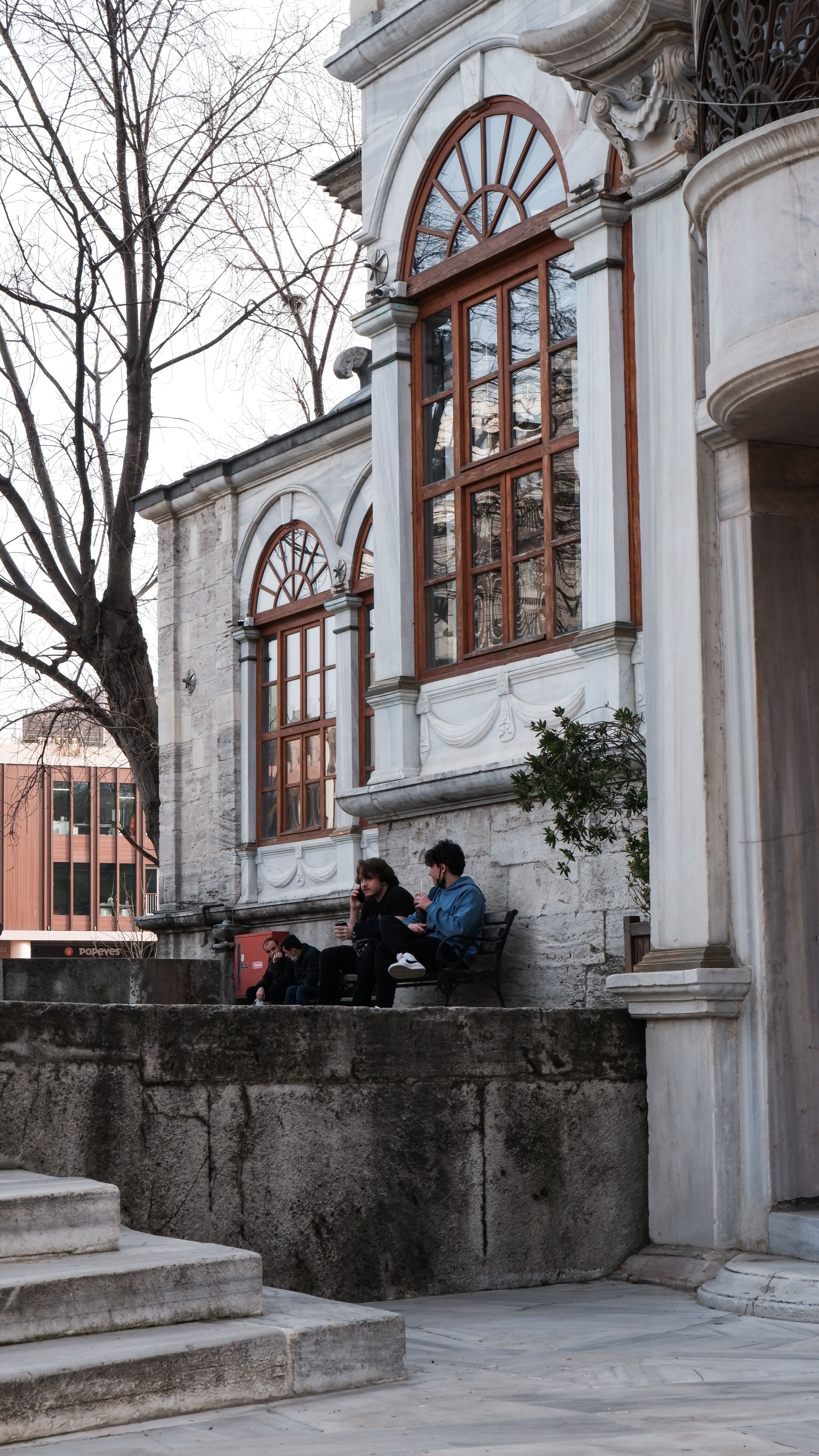 People Sitting by Vintage Building Wall · Free Stock Photo