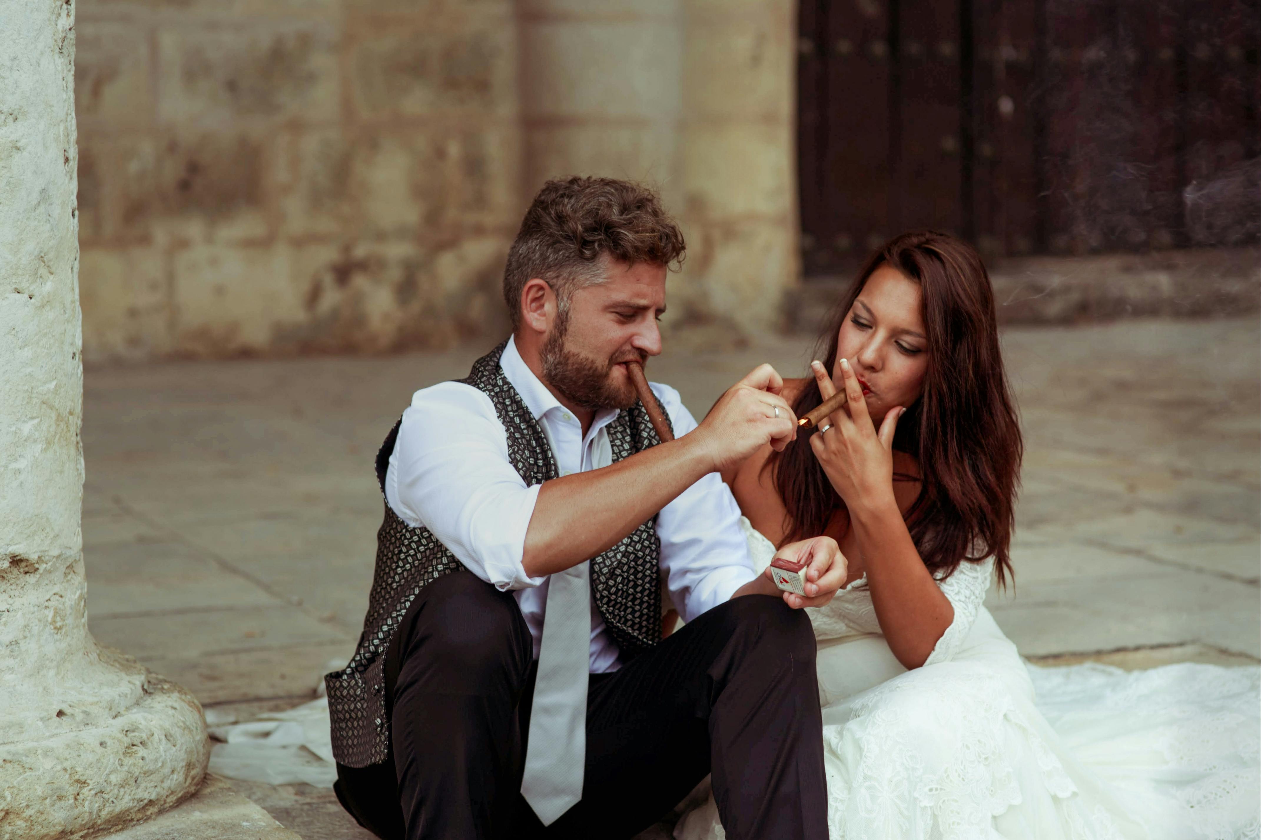 Bride and Groom Smoking Cigars Outdoors · Free Stock Photo