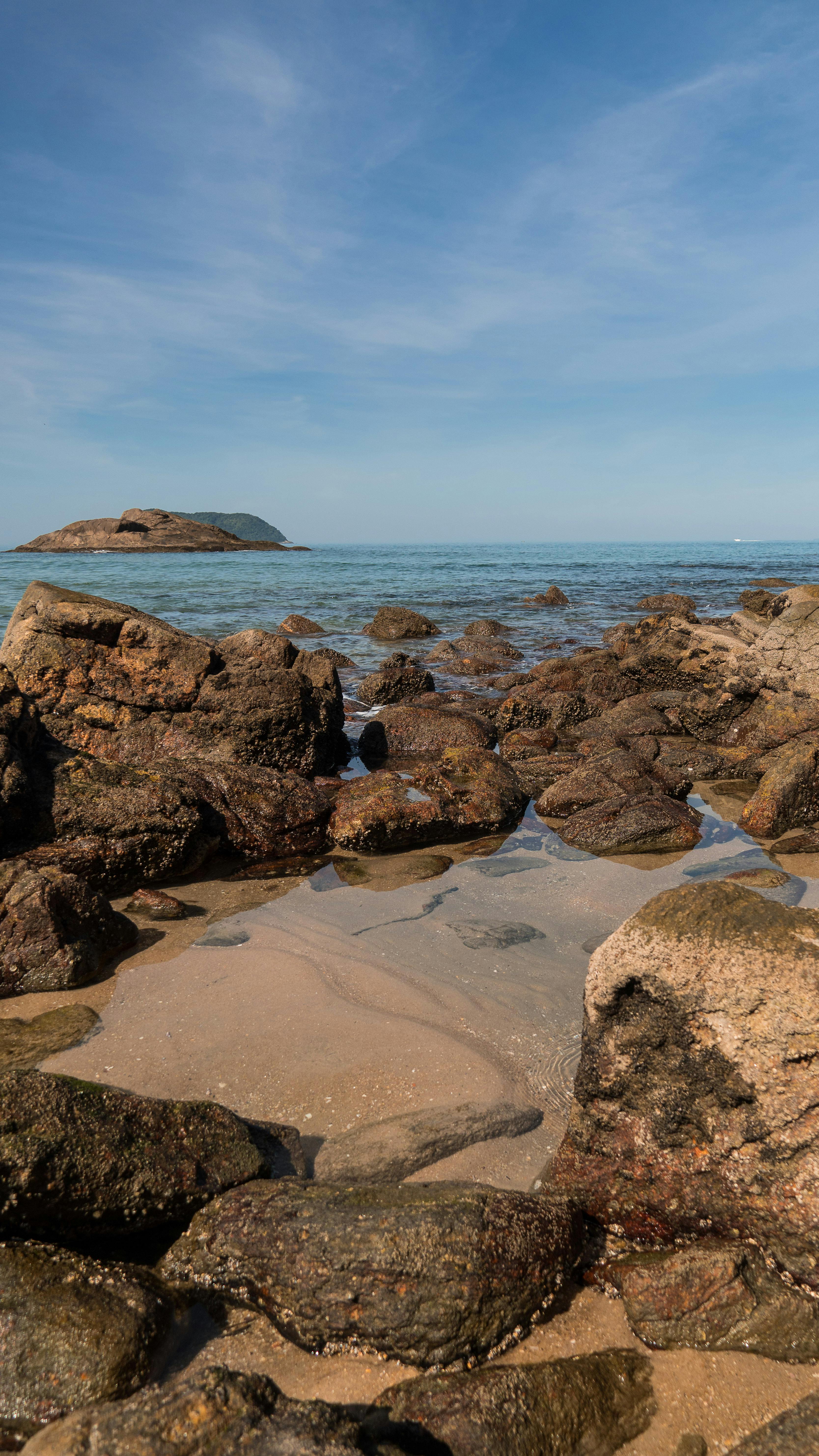 Landscape Photography of Rocks With Moss Surrounded by Body of Water ...
