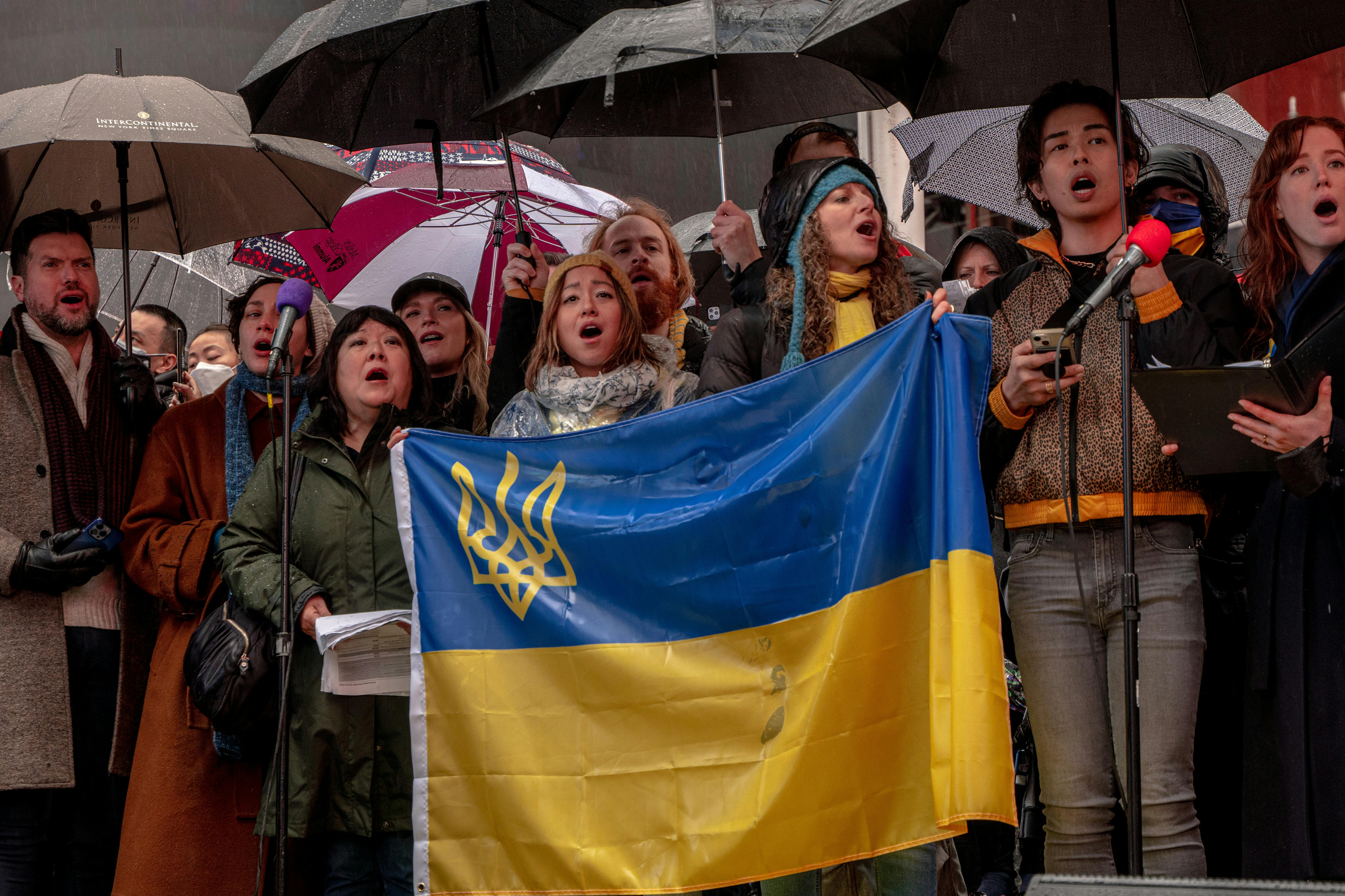 A Group of People Holding a Yellow and Blue Flag Singing · Free Stock Photo