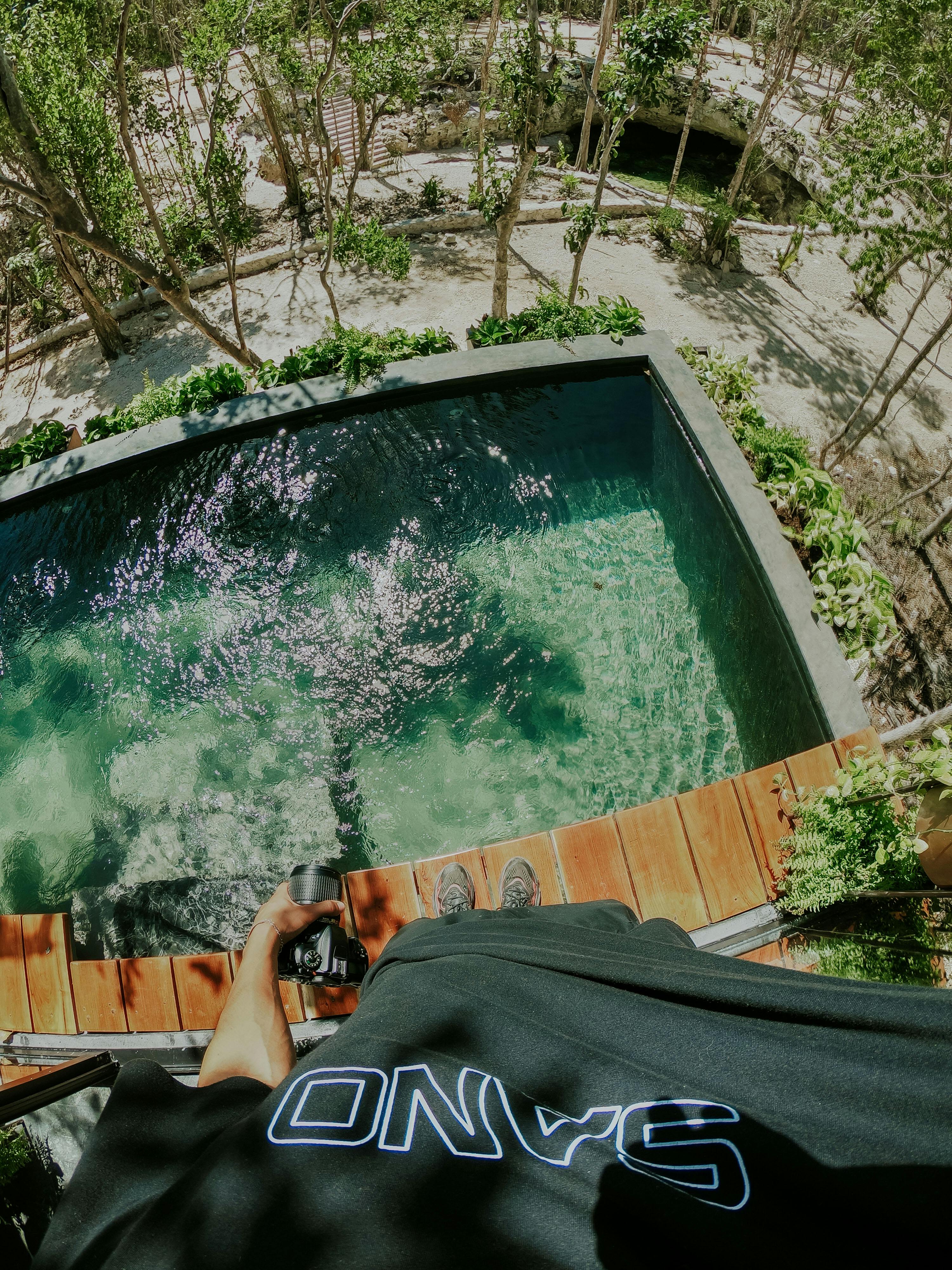 A Person Holding a Camera Standing Beside a Swimming Pool · Free Stock ...