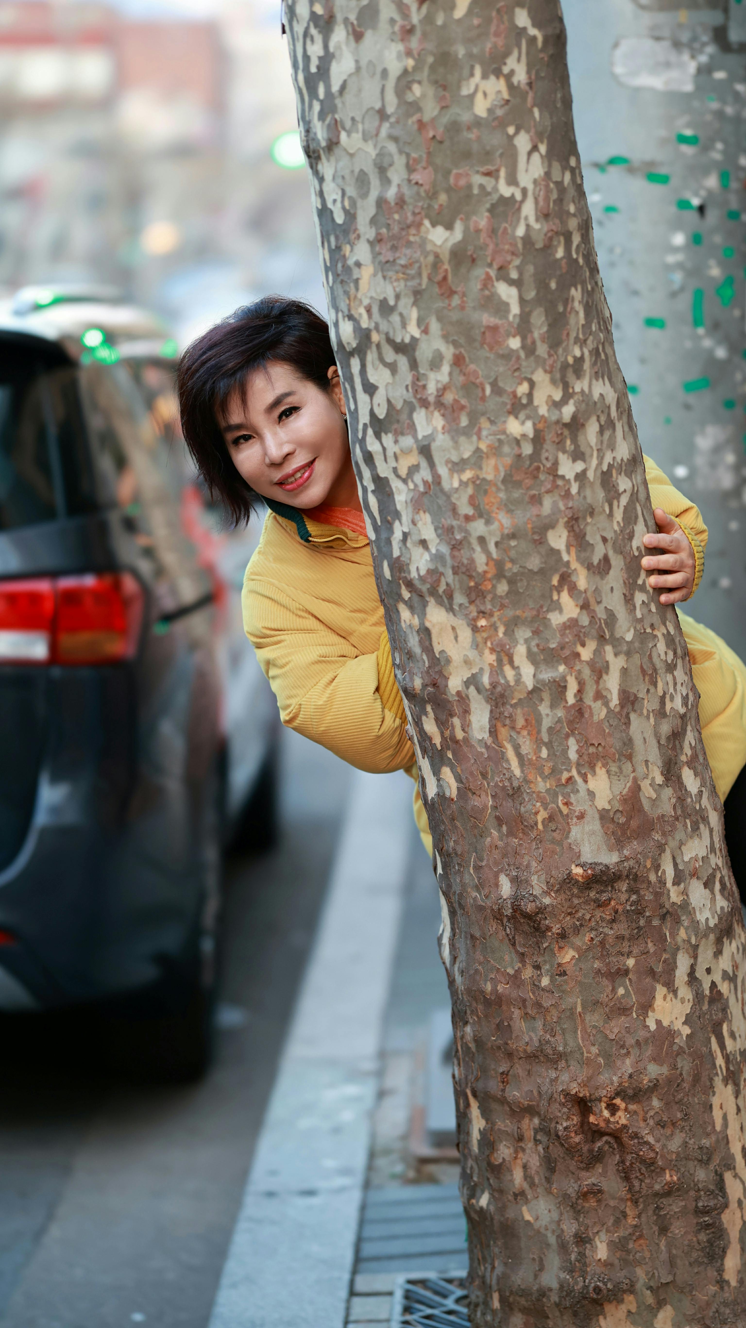 Woman Standing Behind a Tree Trunk · Free Stock Photo