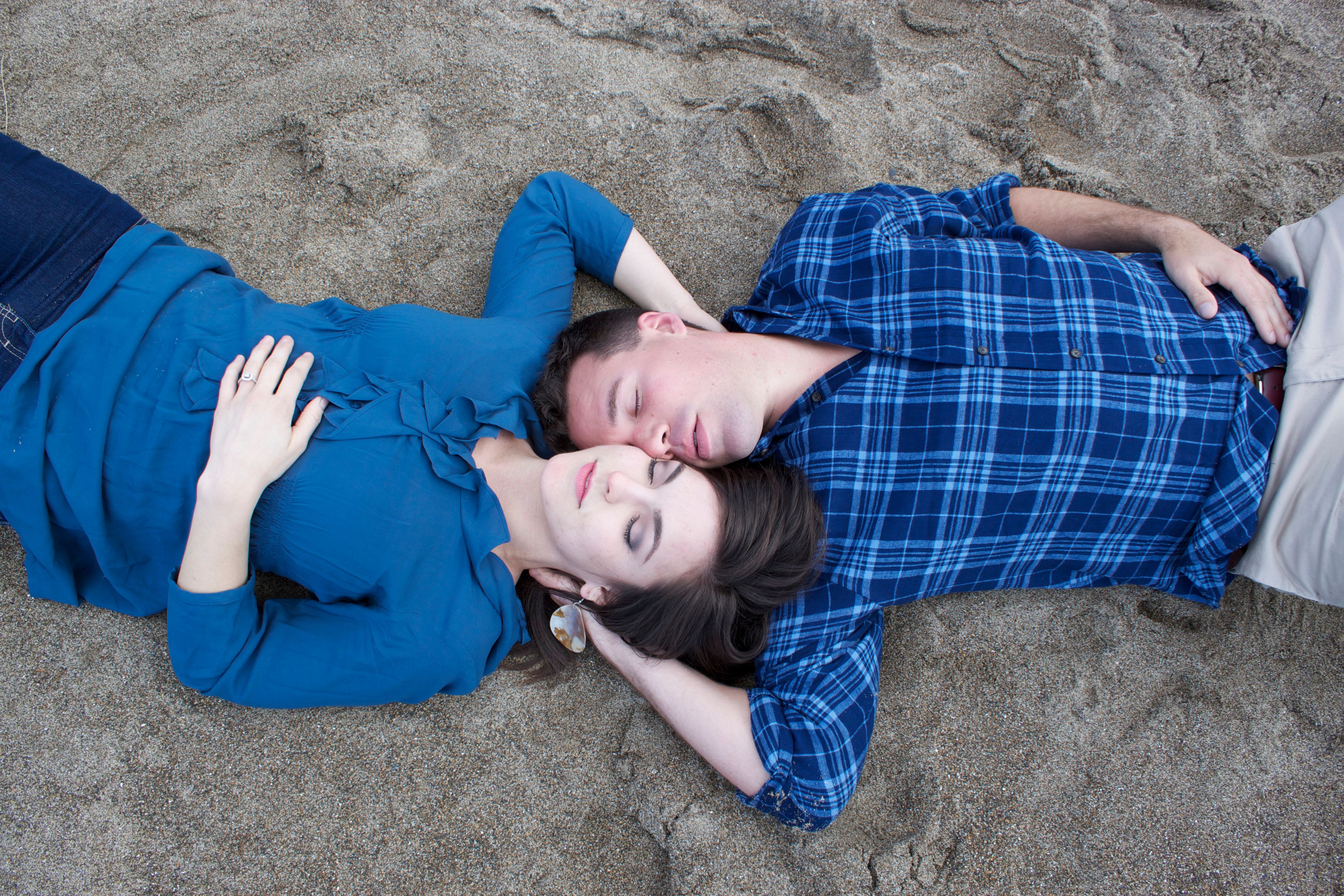 High-Angle Shot of a Romantic Couple Lying on Beach Sand · Free Stock Photo