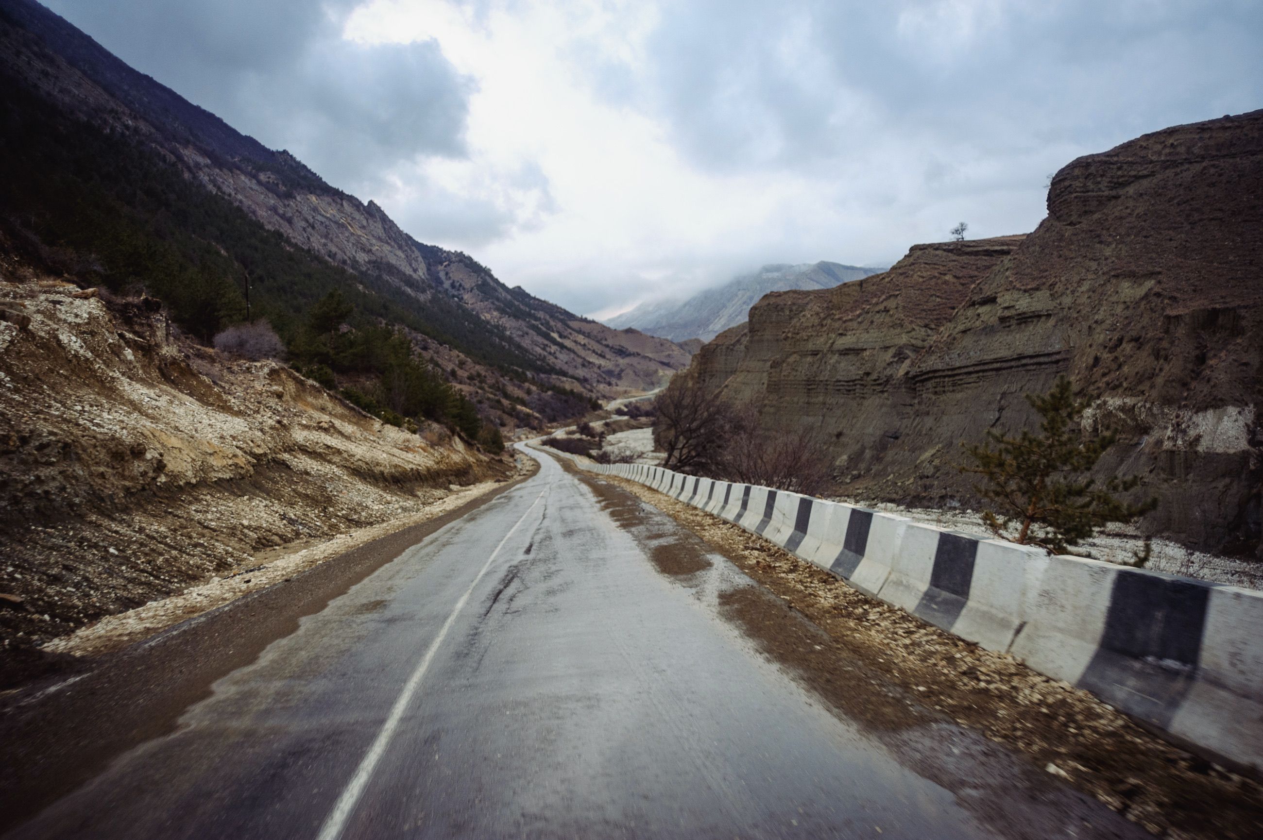 An Empty Road with Concrete Barriers Near the Mountains · Free Stock Photo