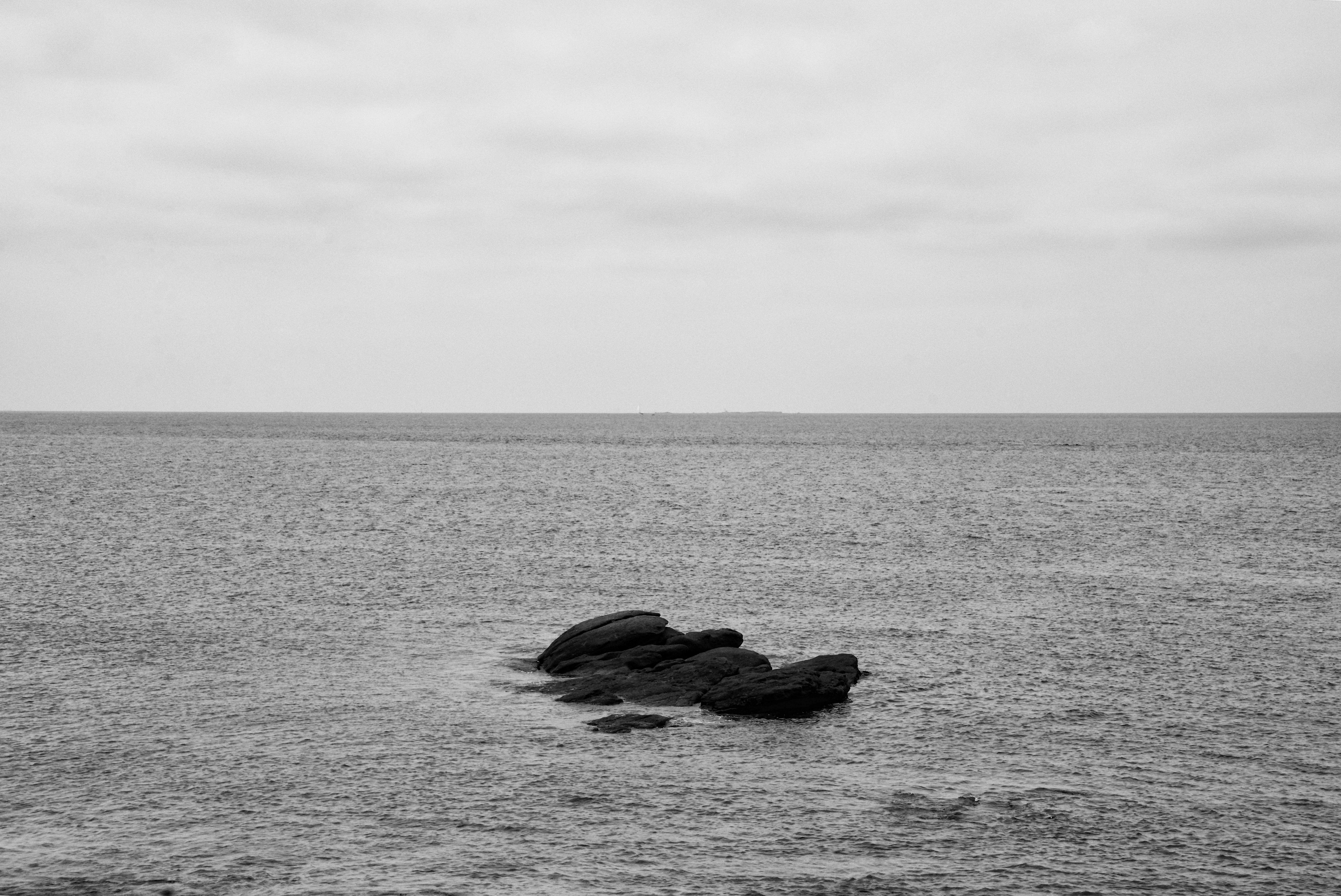 Grayscale Photo of a Rock Formation on the Sea · Free Stock Photo
