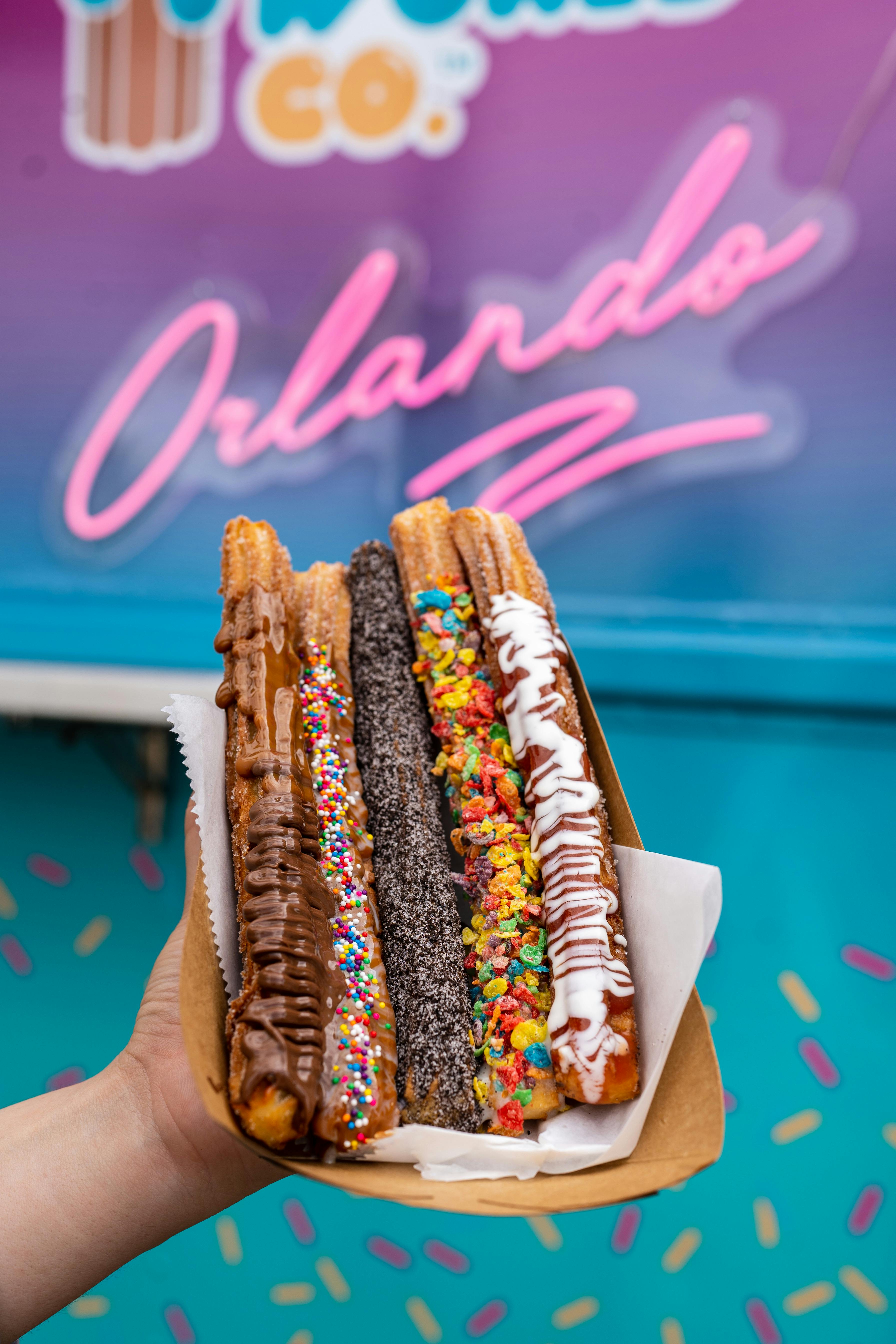 A Person Holding a Bunch of Churros with Toppings · Free Stock Photo