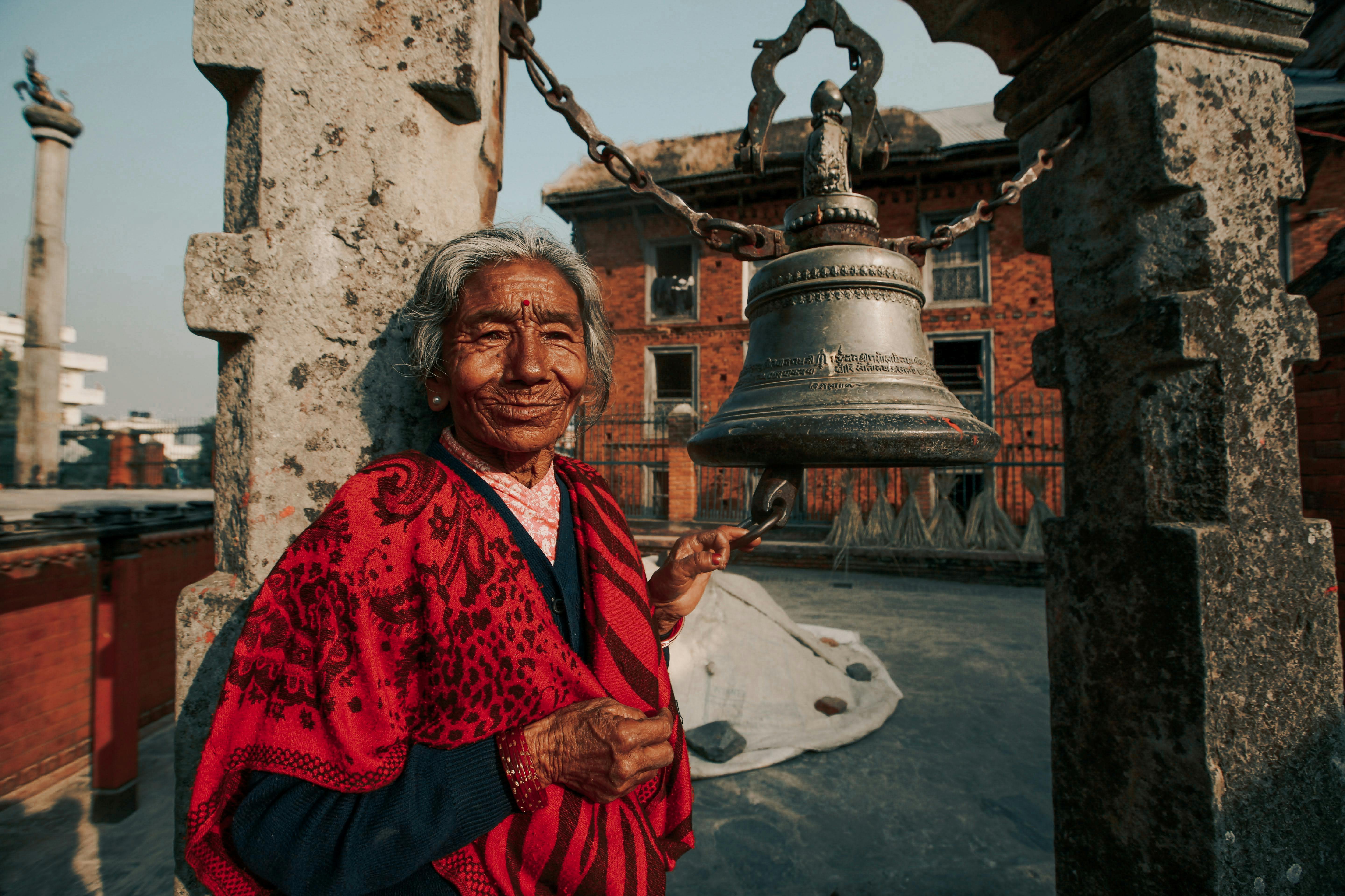 Smiling Elderly Woman beside a Bell · Free Stock Photo
