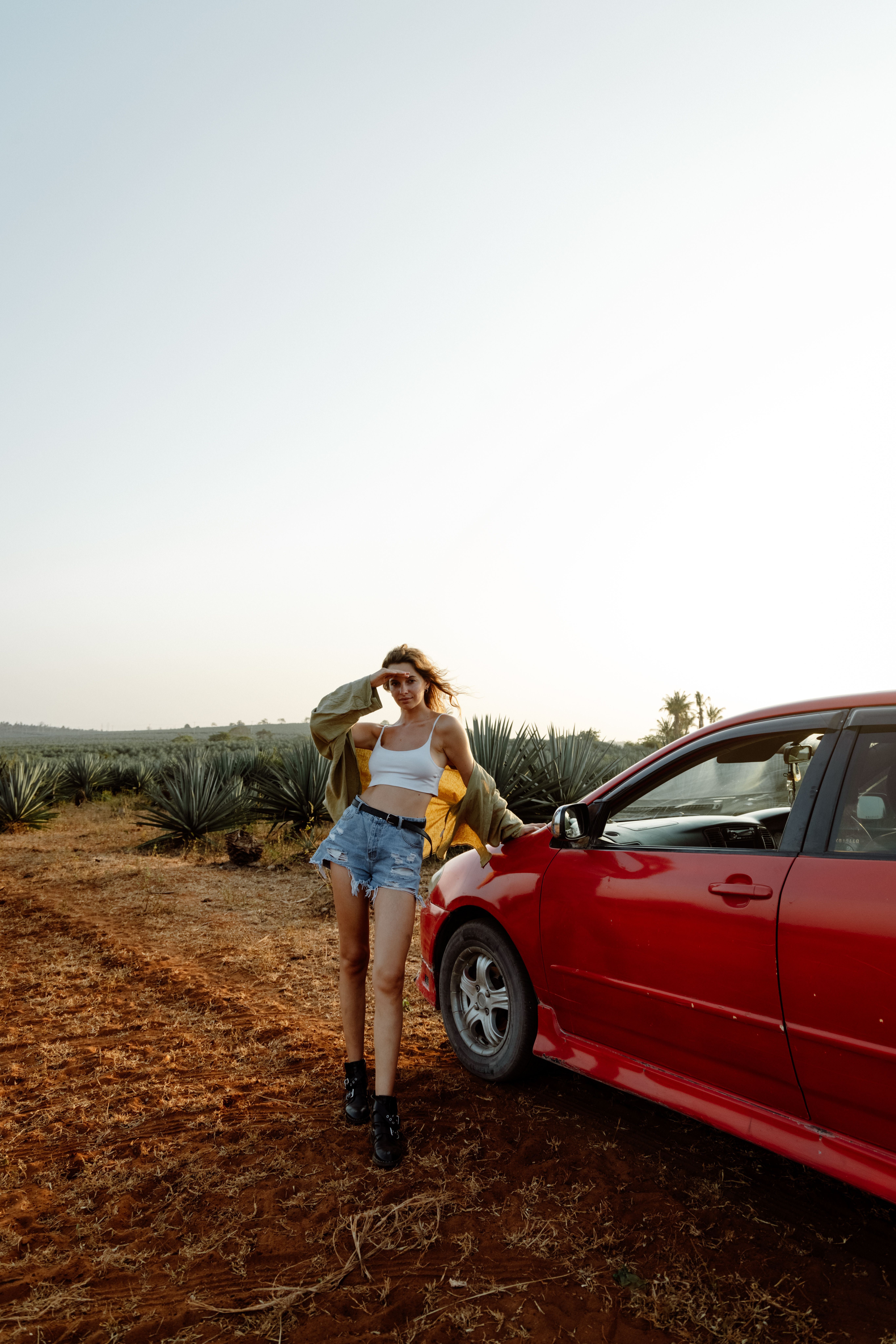 A Woman Posing Beside a Red Car · Free Stock Photo