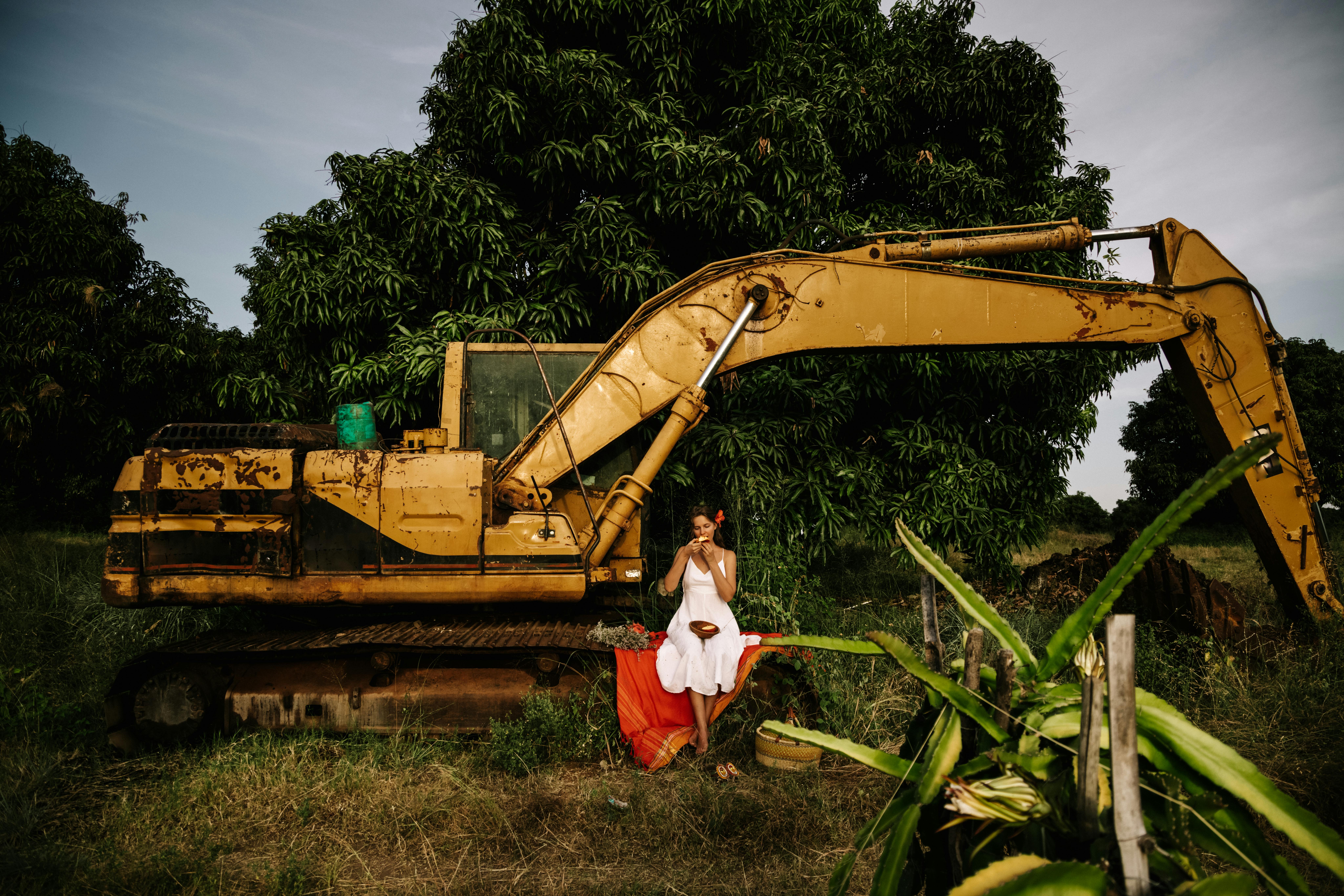 A Woman Eating while Sitting on a Backhoe · Free Stock Photo