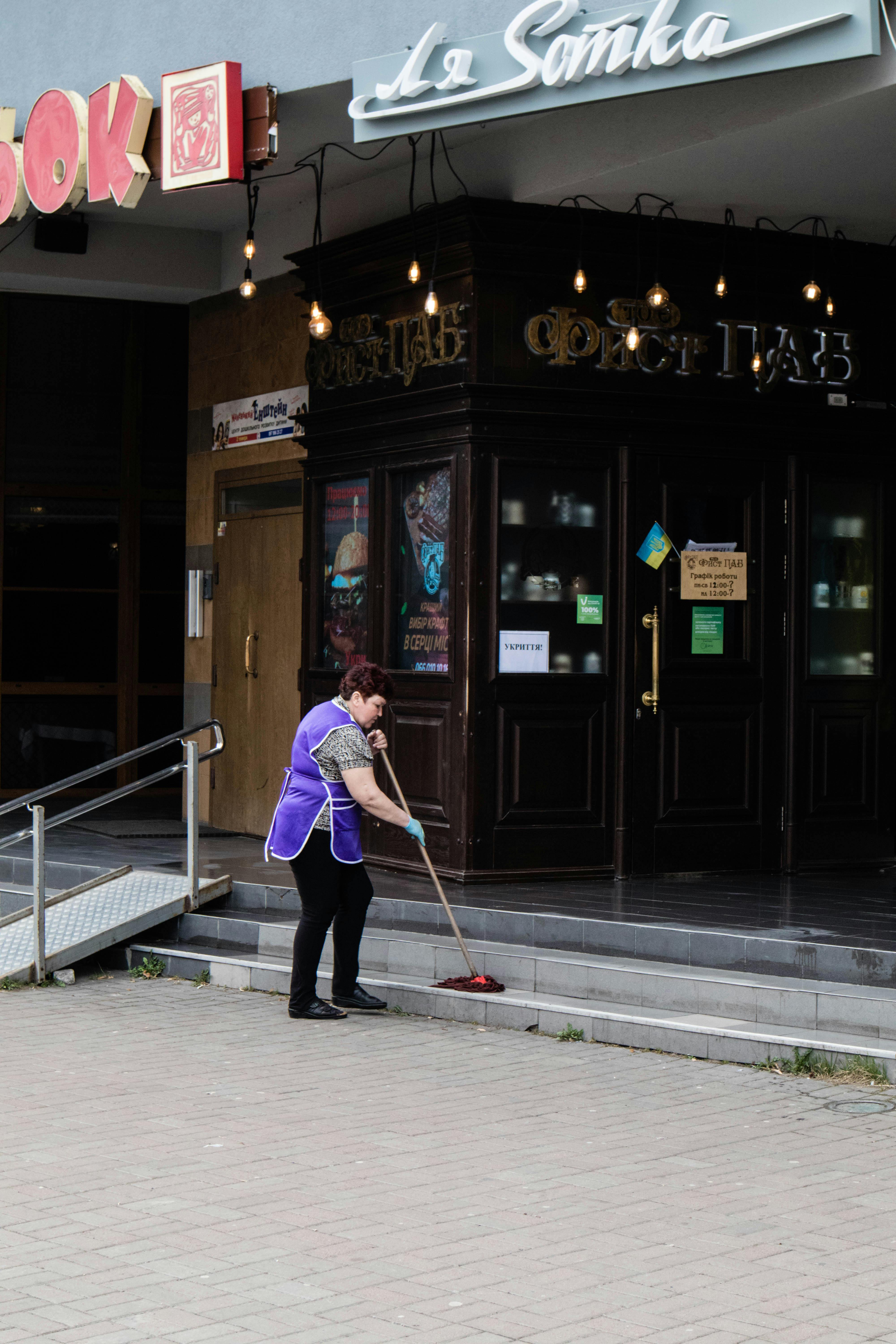 A Woman Mopping the Steps outside a Building · Free Stock Photo