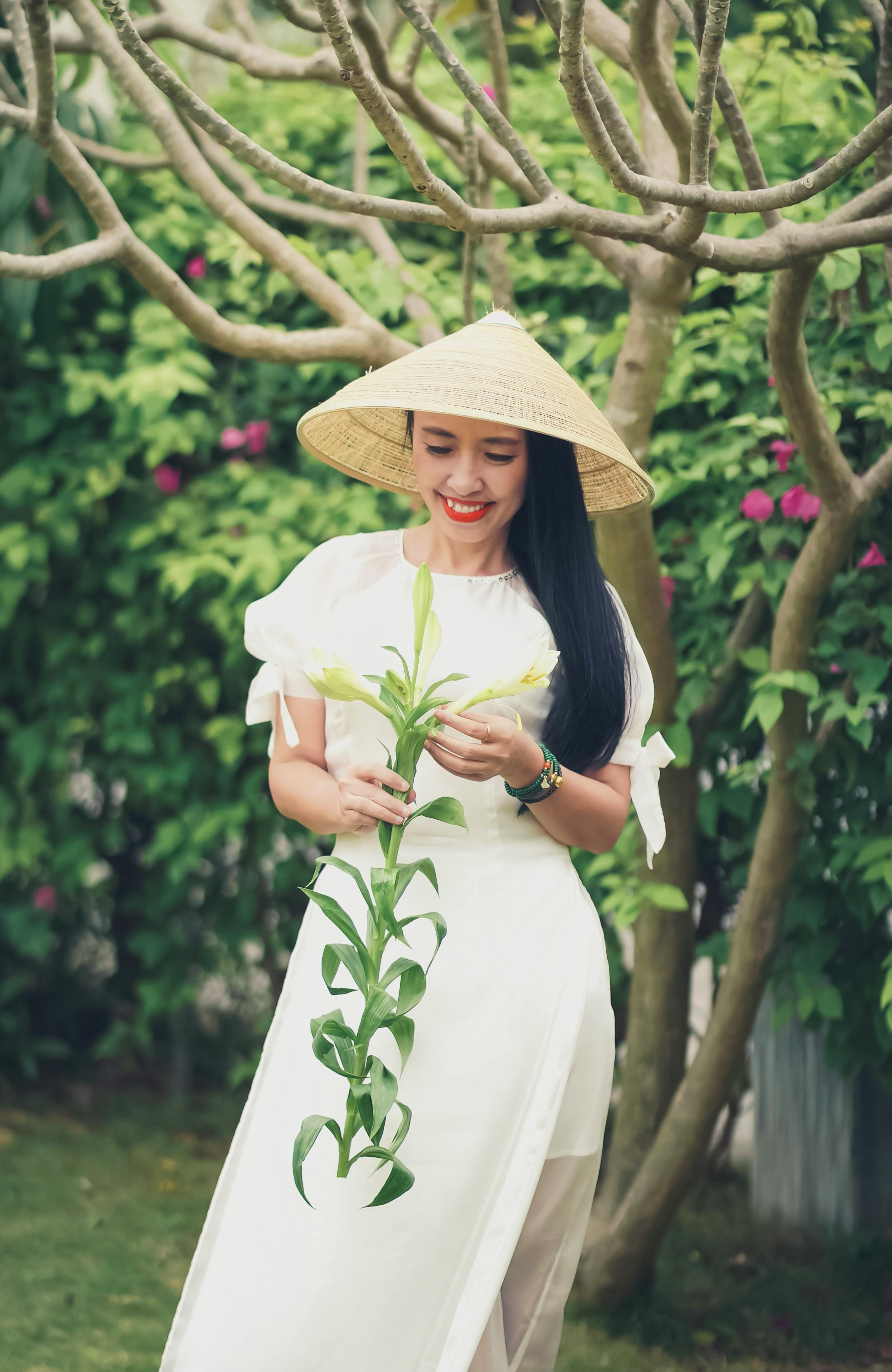 Woman Wearing White Dress and Asian Traditional Hat Holding a Plant in ...
