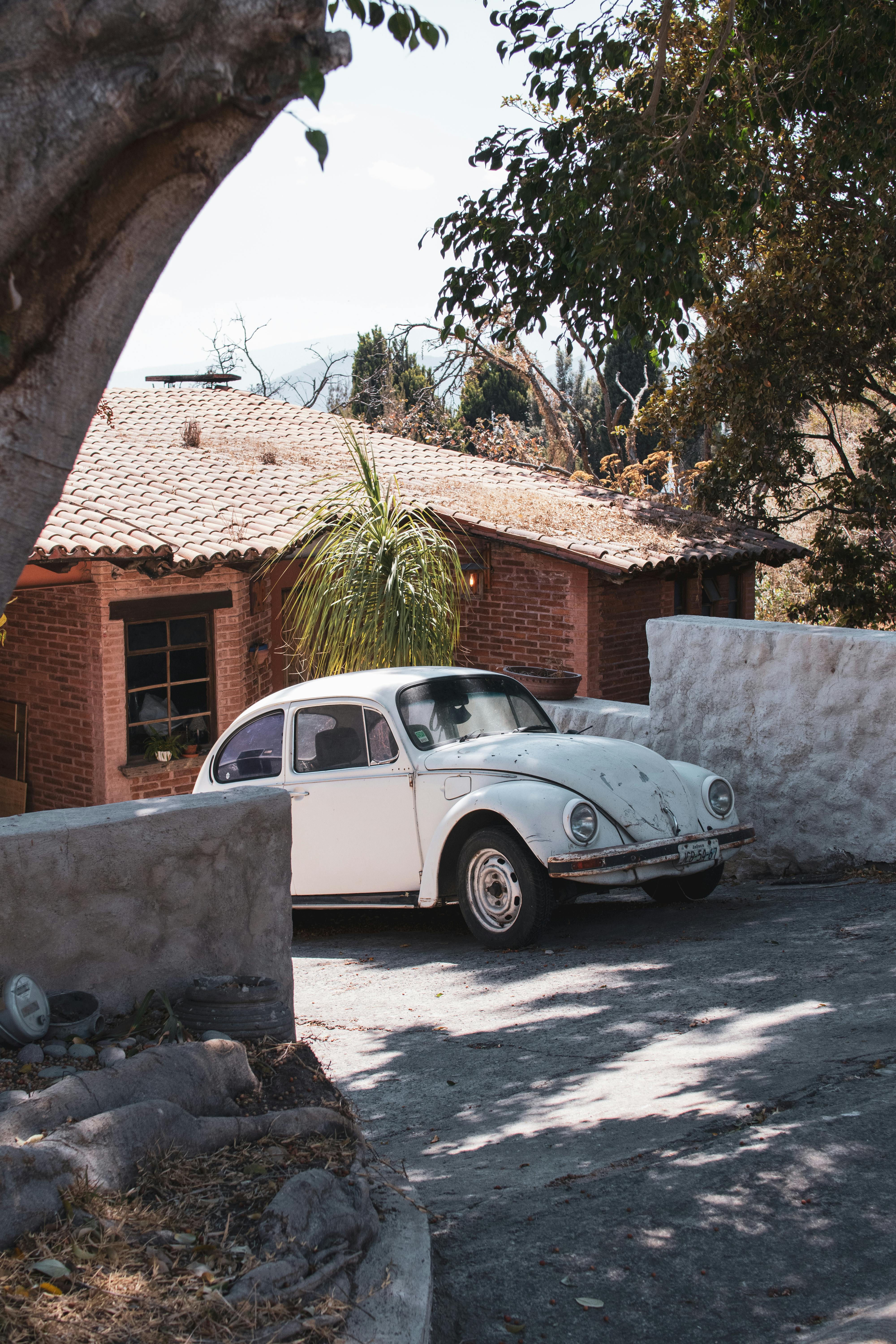 Brown Volkswagen Beetle Parked Outside Between Buildings · Free Stock Photo