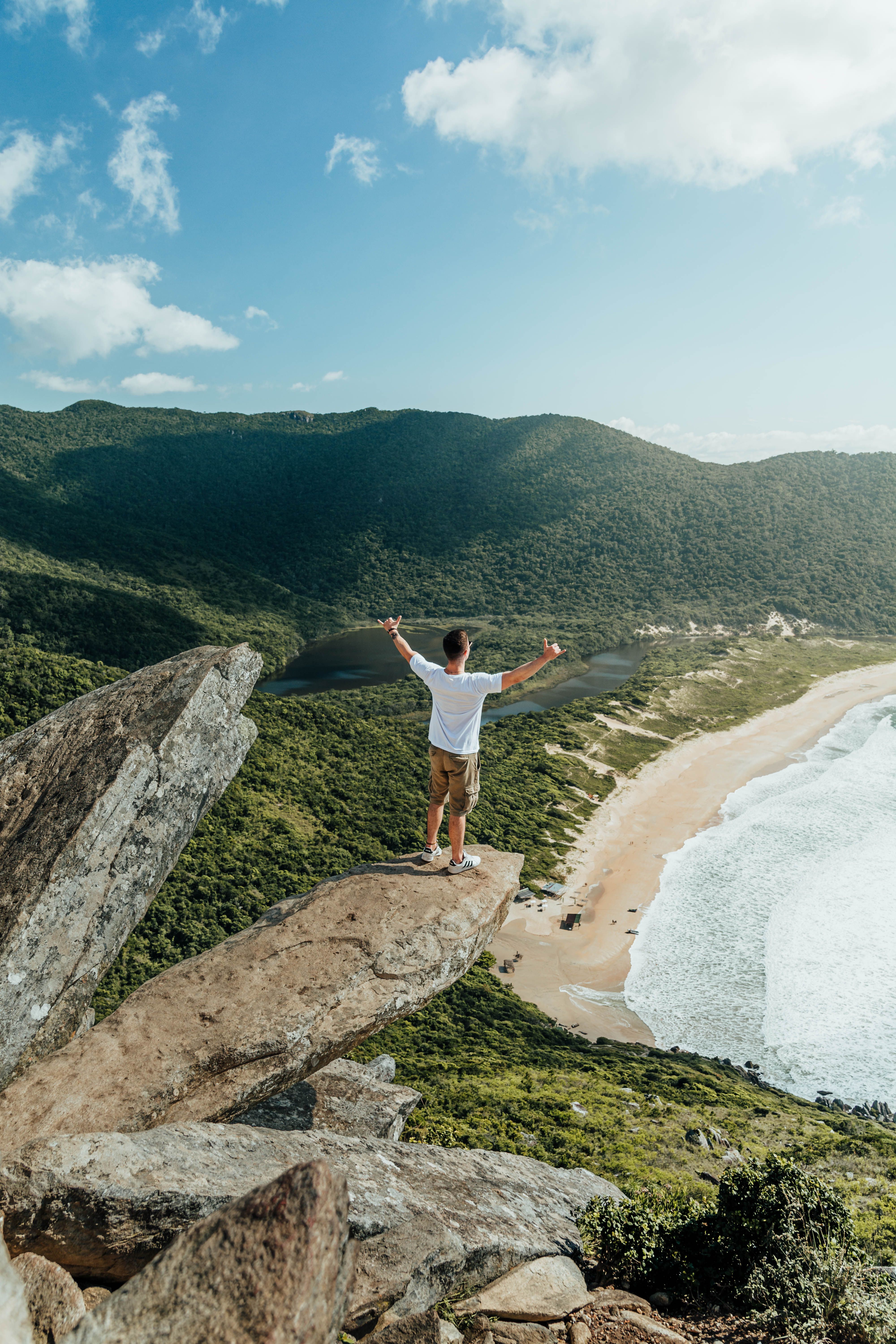 Man Standing on a Cliff Near a Body of Water · Free Stock Photo