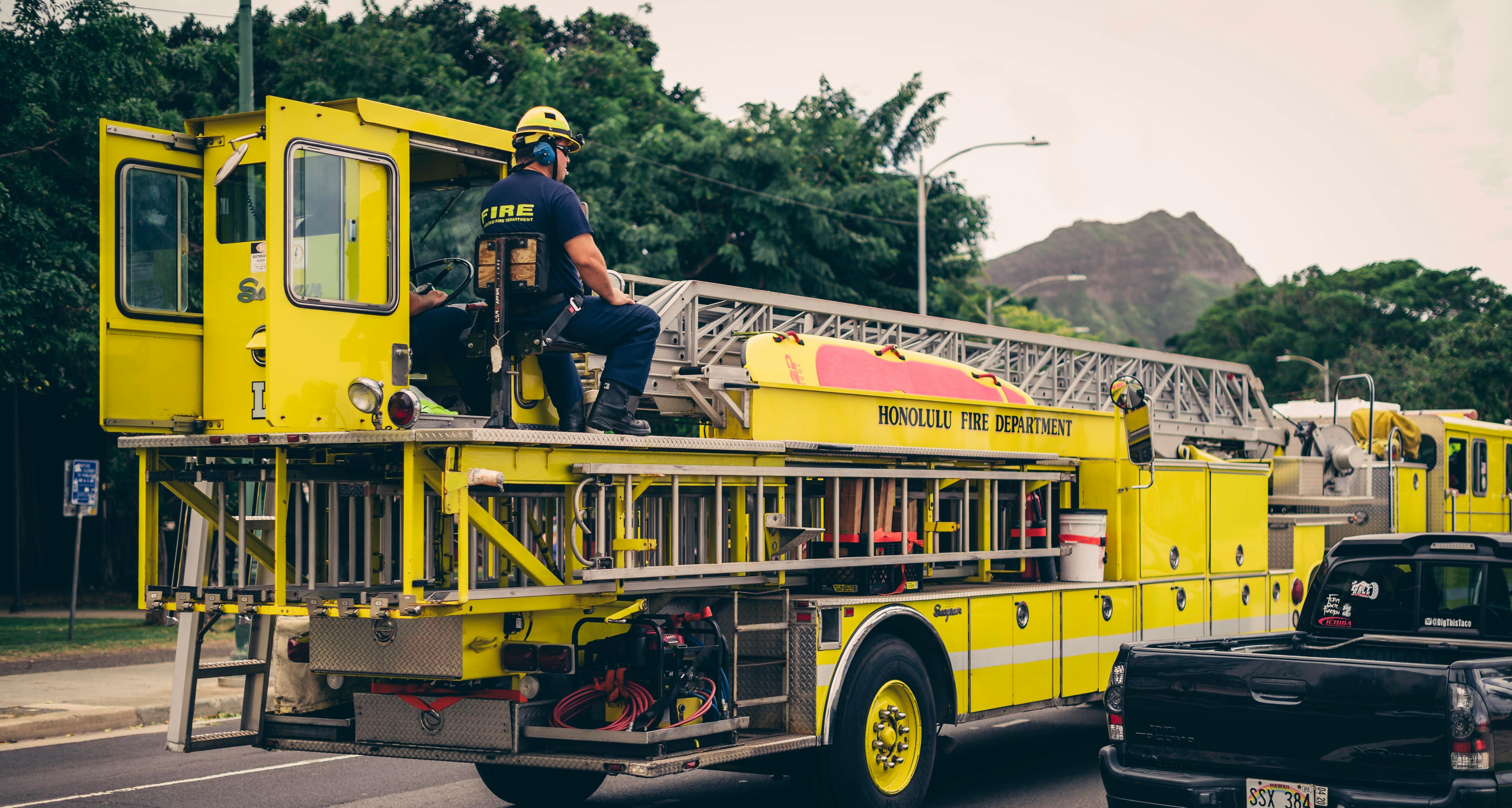 Man Sitting on a Yellow Fire Truck · Free Stock Photo