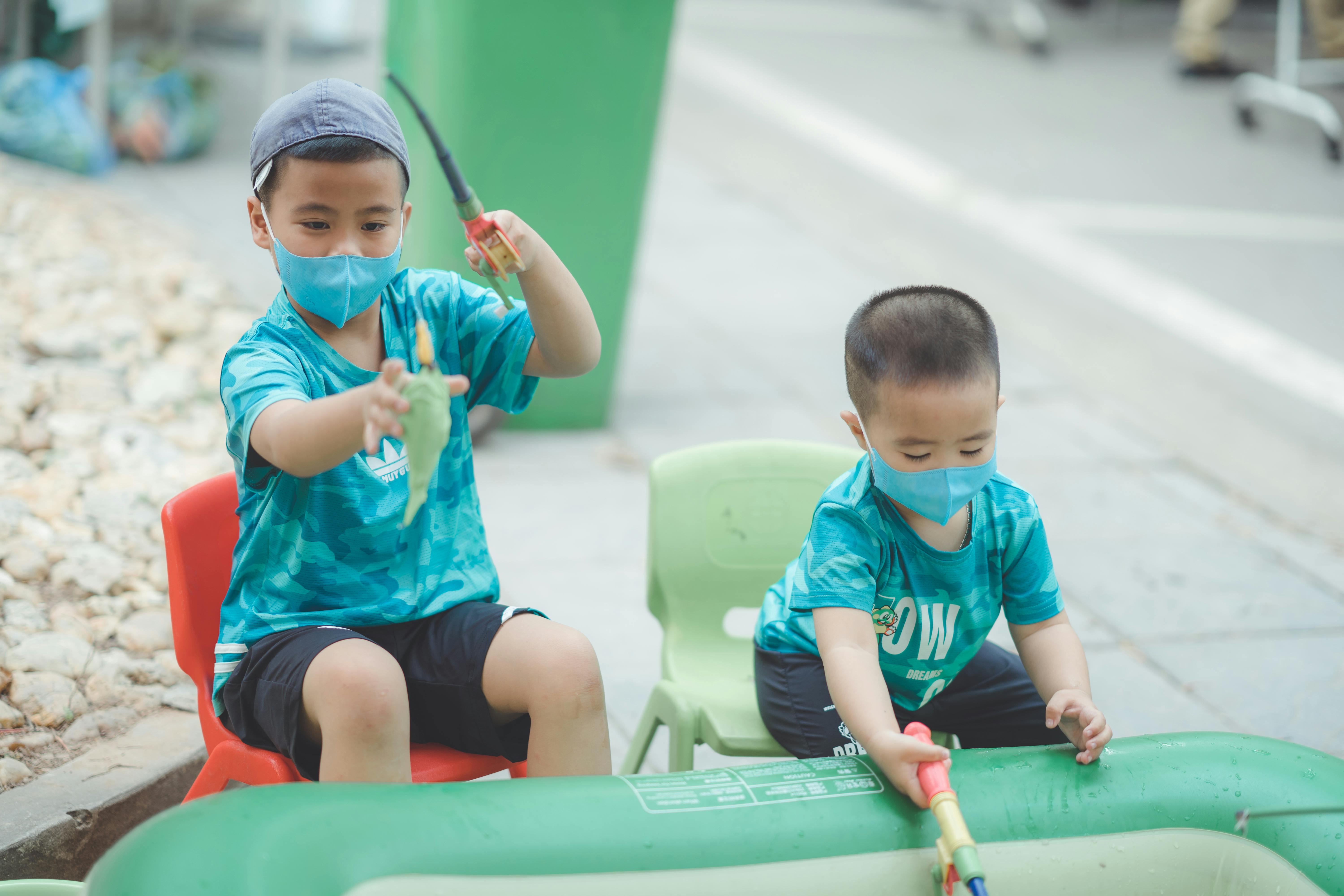 Happy Kids in Face Masks Playing with Fishing Rods · Free Stock Photo