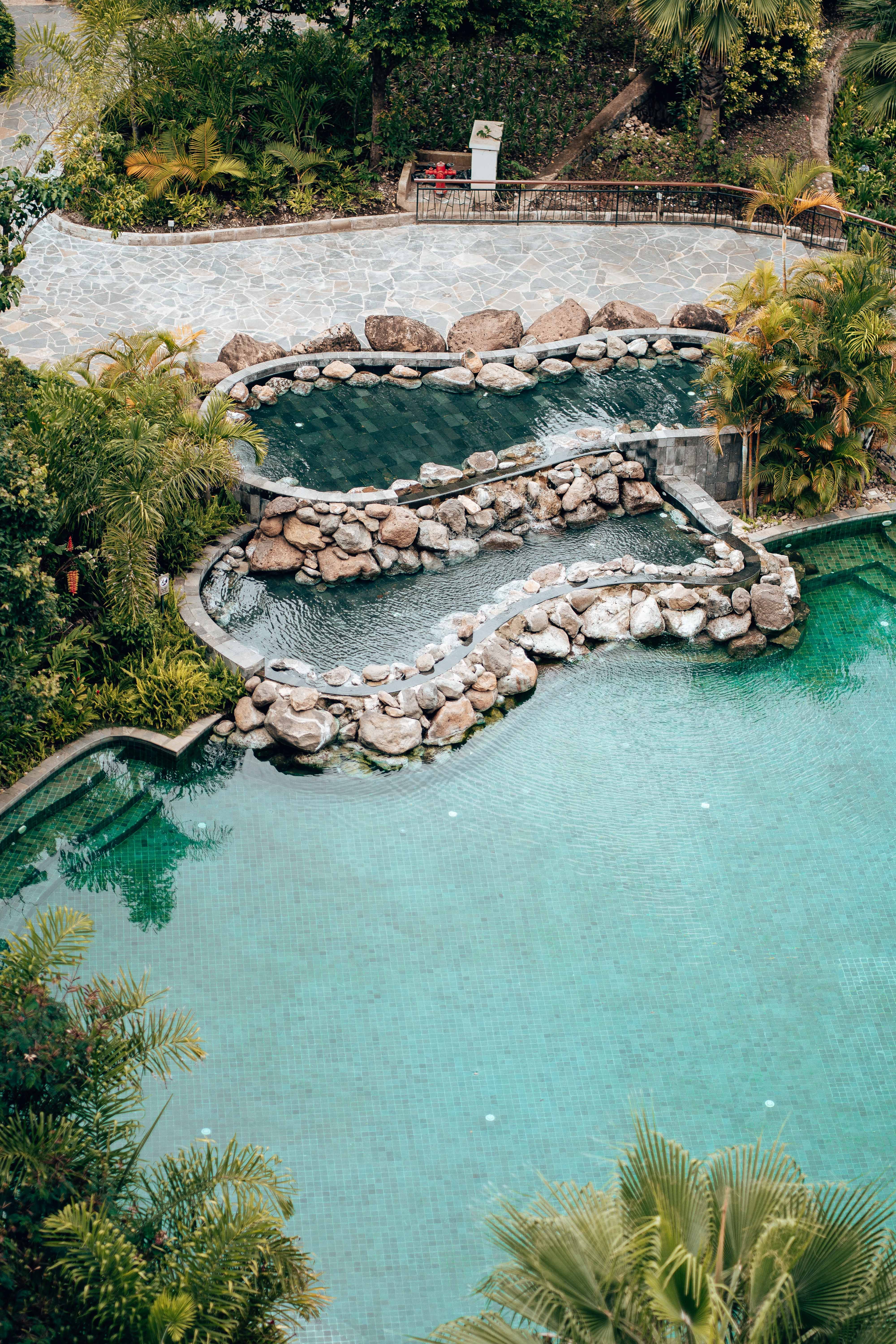High Angle Shot of a Swimming Pool Designed with Rocks and Green Plants ...