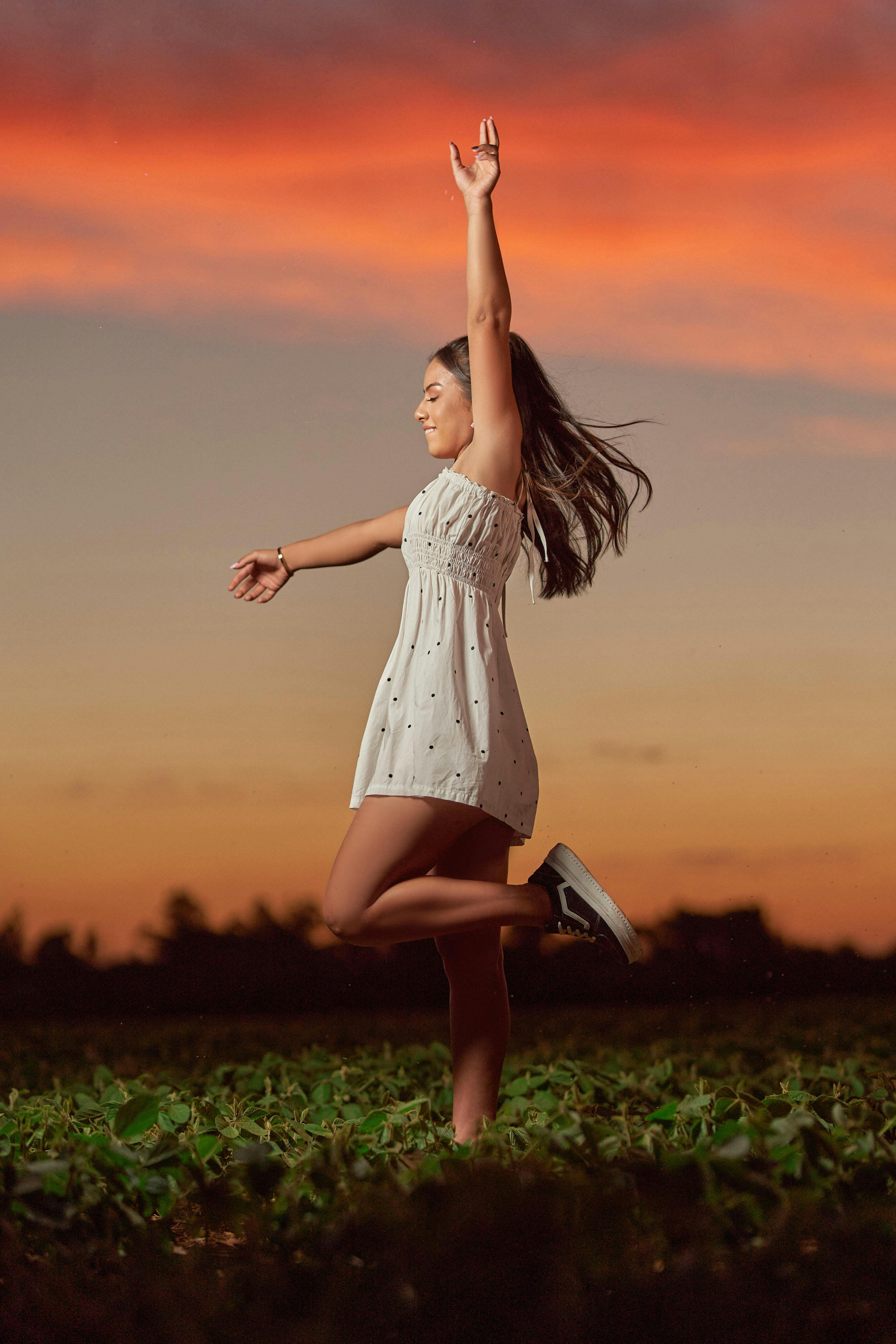 A Woman in White Dress Standing One Legged on the Field · Free Stock Photo