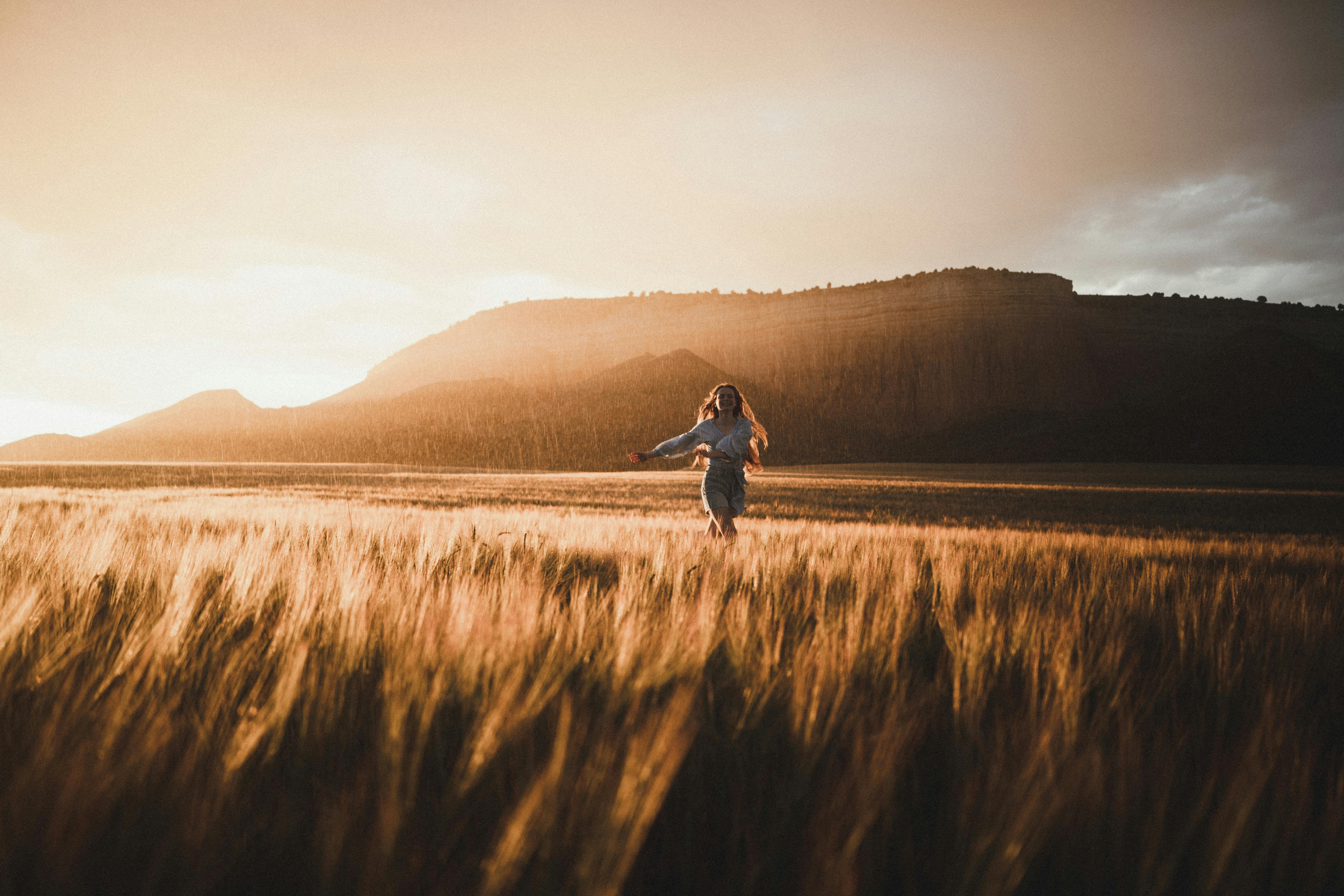 Woman Running Through a Field at Sunset · Free Stock Photo