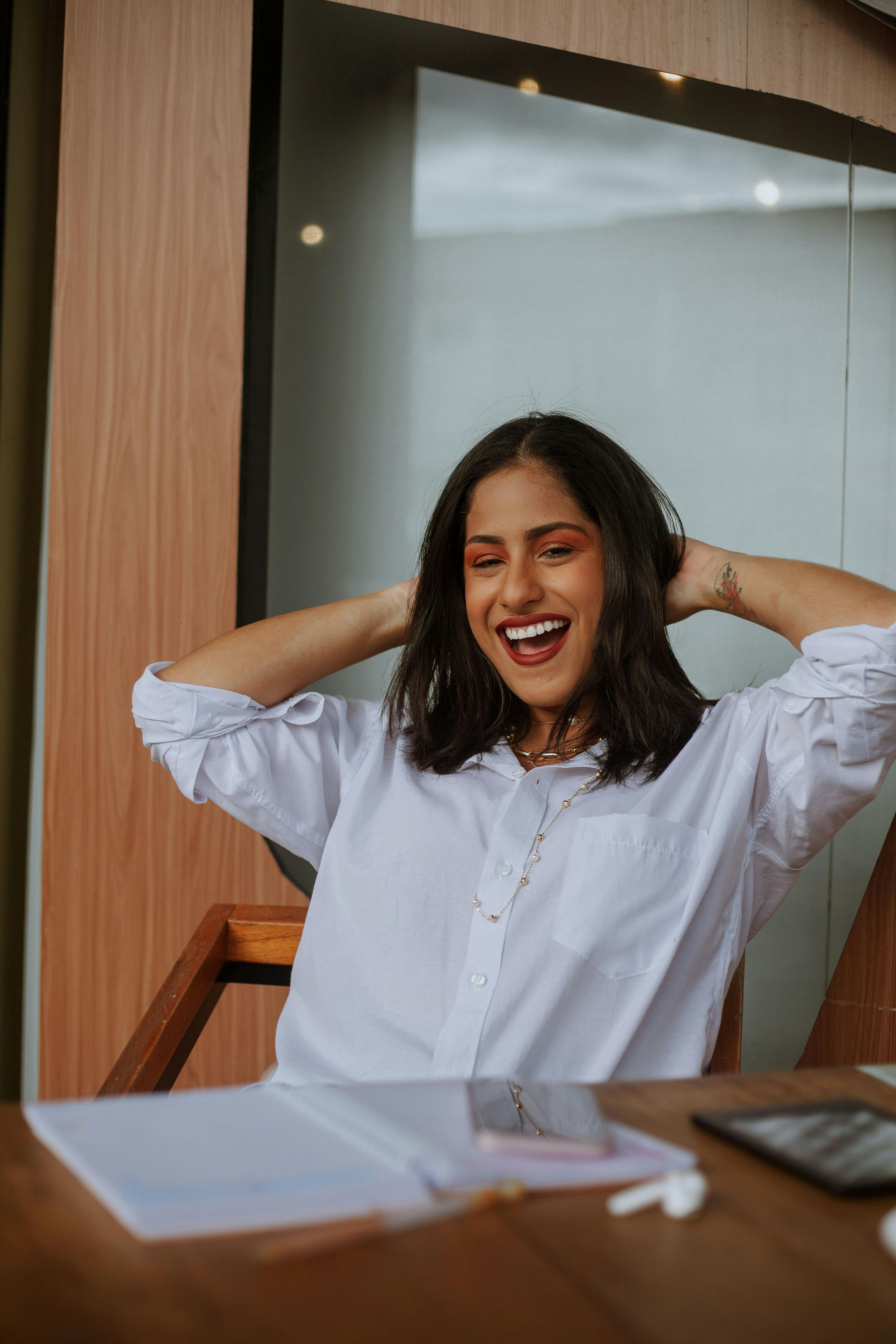 Young Woman Sitting in an Office and Smiling · Free Stock Photo