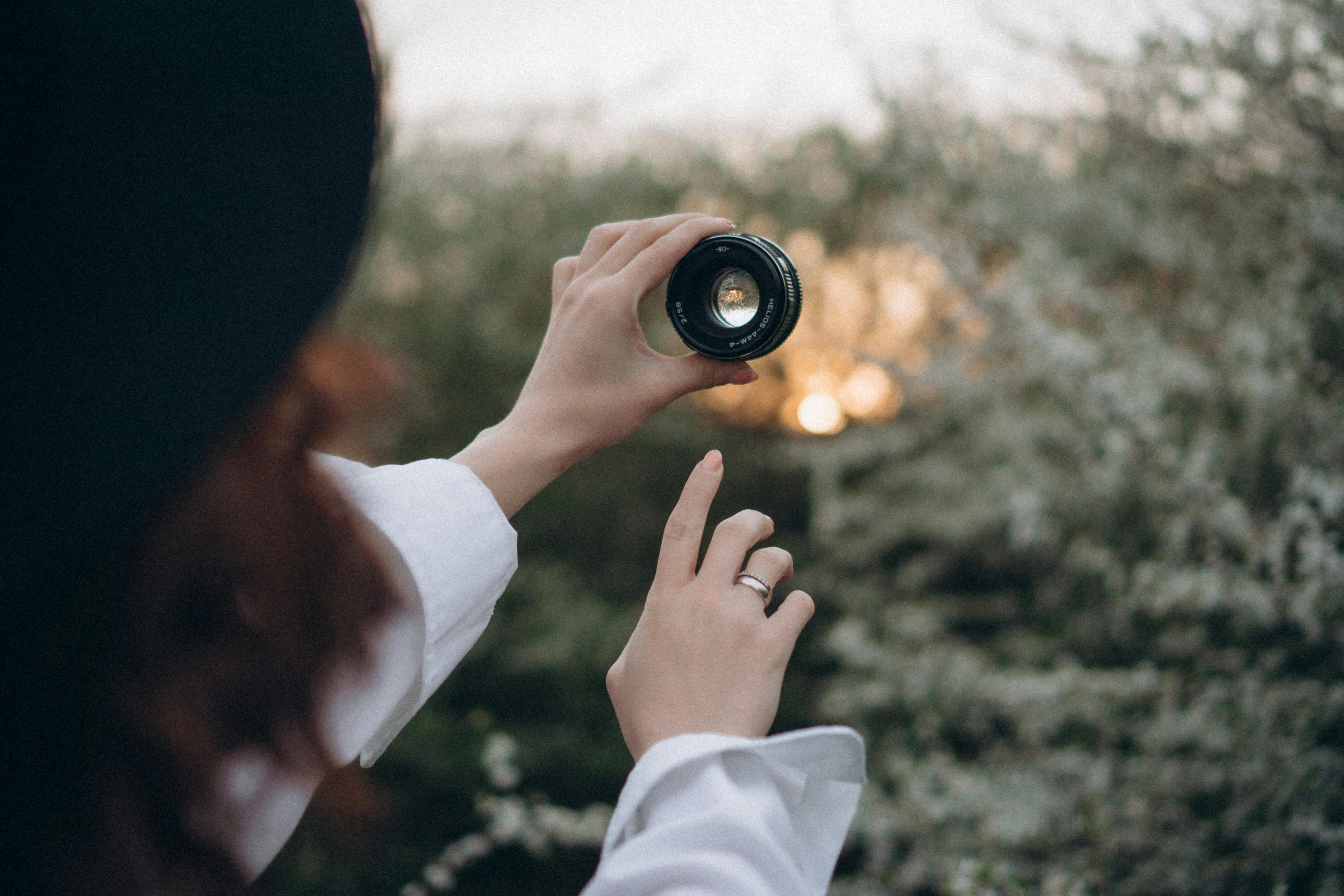 Close-Up Shot of a Person Holding Camera Lens · Free Stock Photo