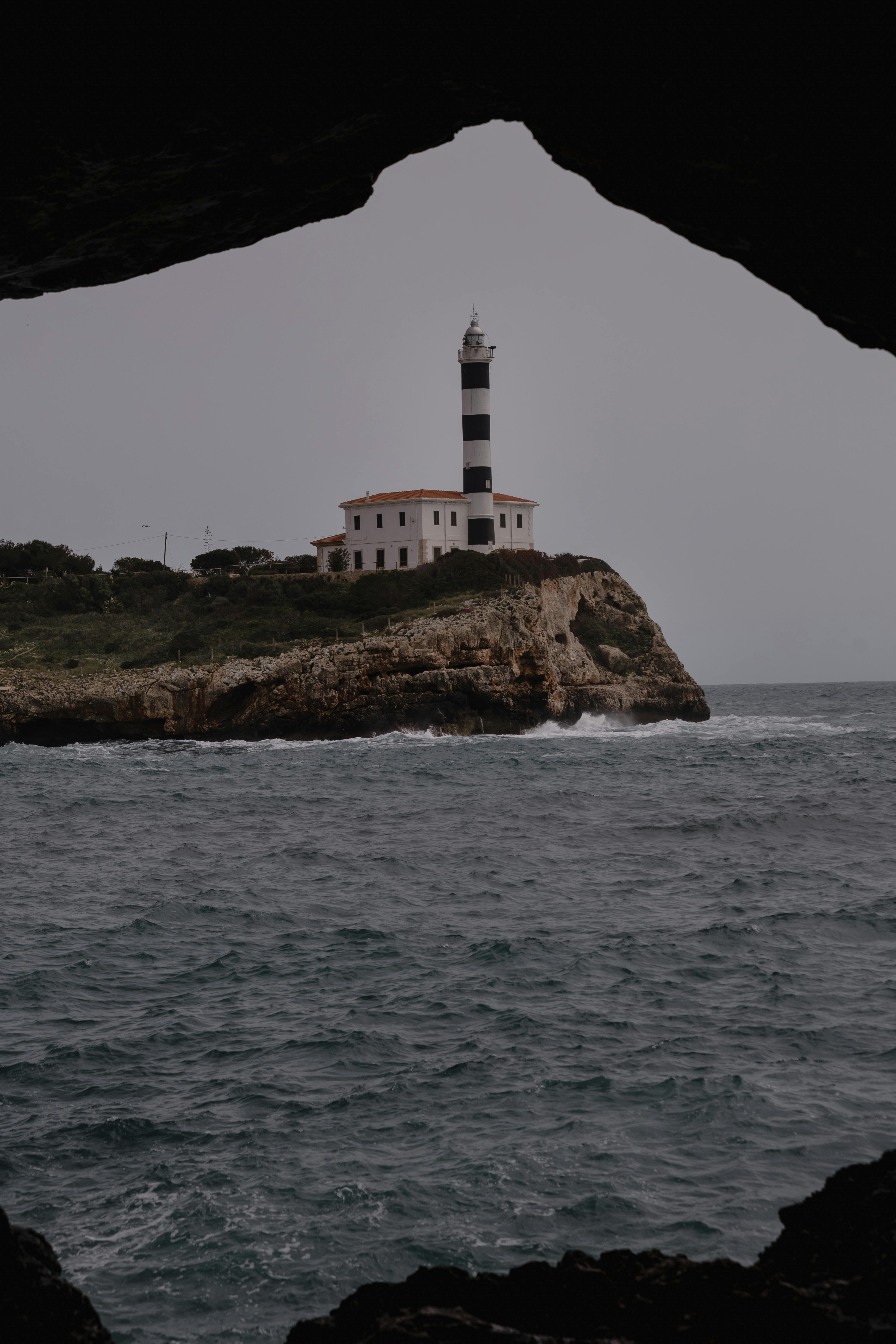 White and Black Lighthouse on Brown Rock Formation Near Sea · Free ...