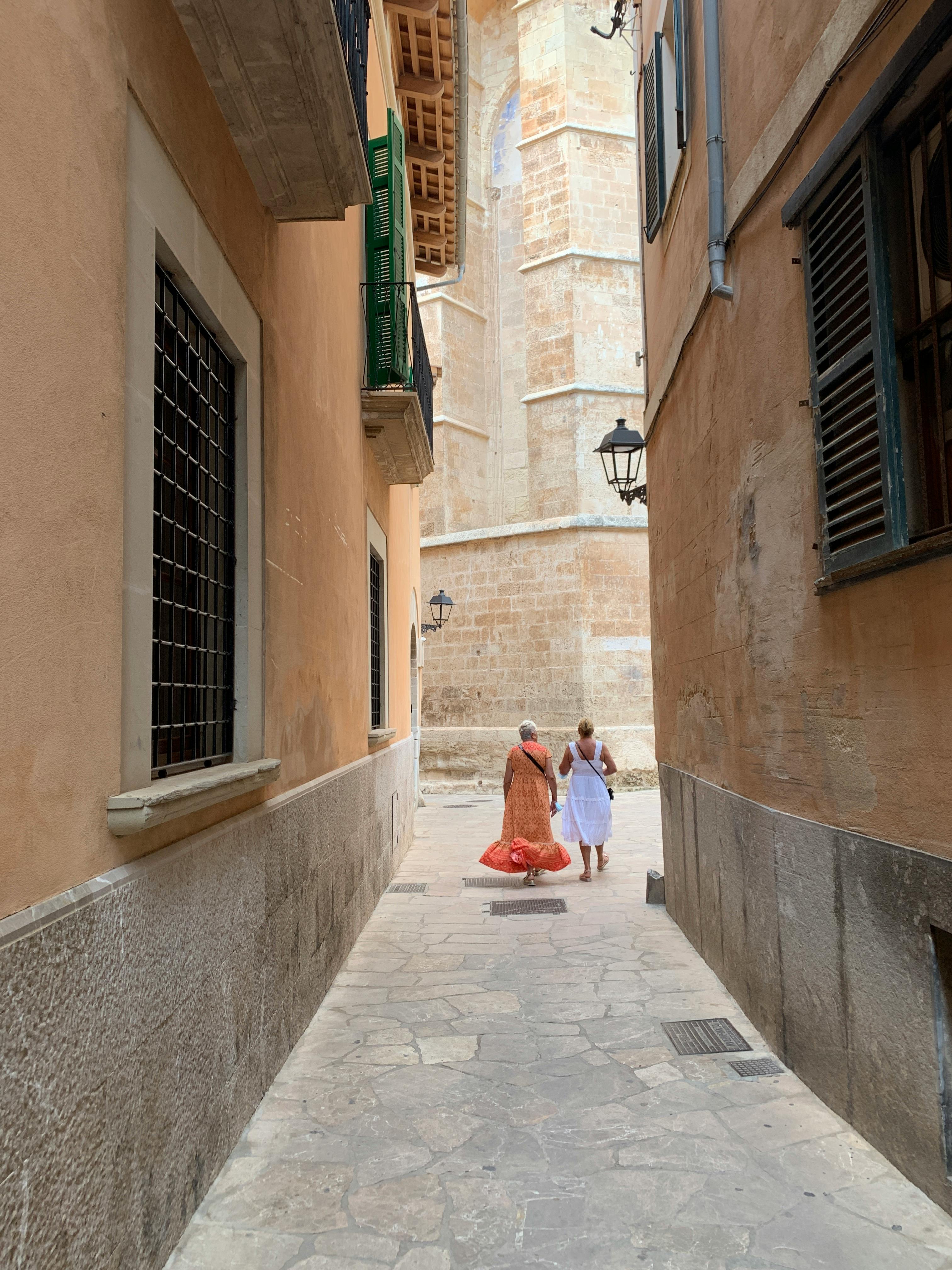 Women Walking Between Buildings in a Narrow Alley · Free Stock Photo