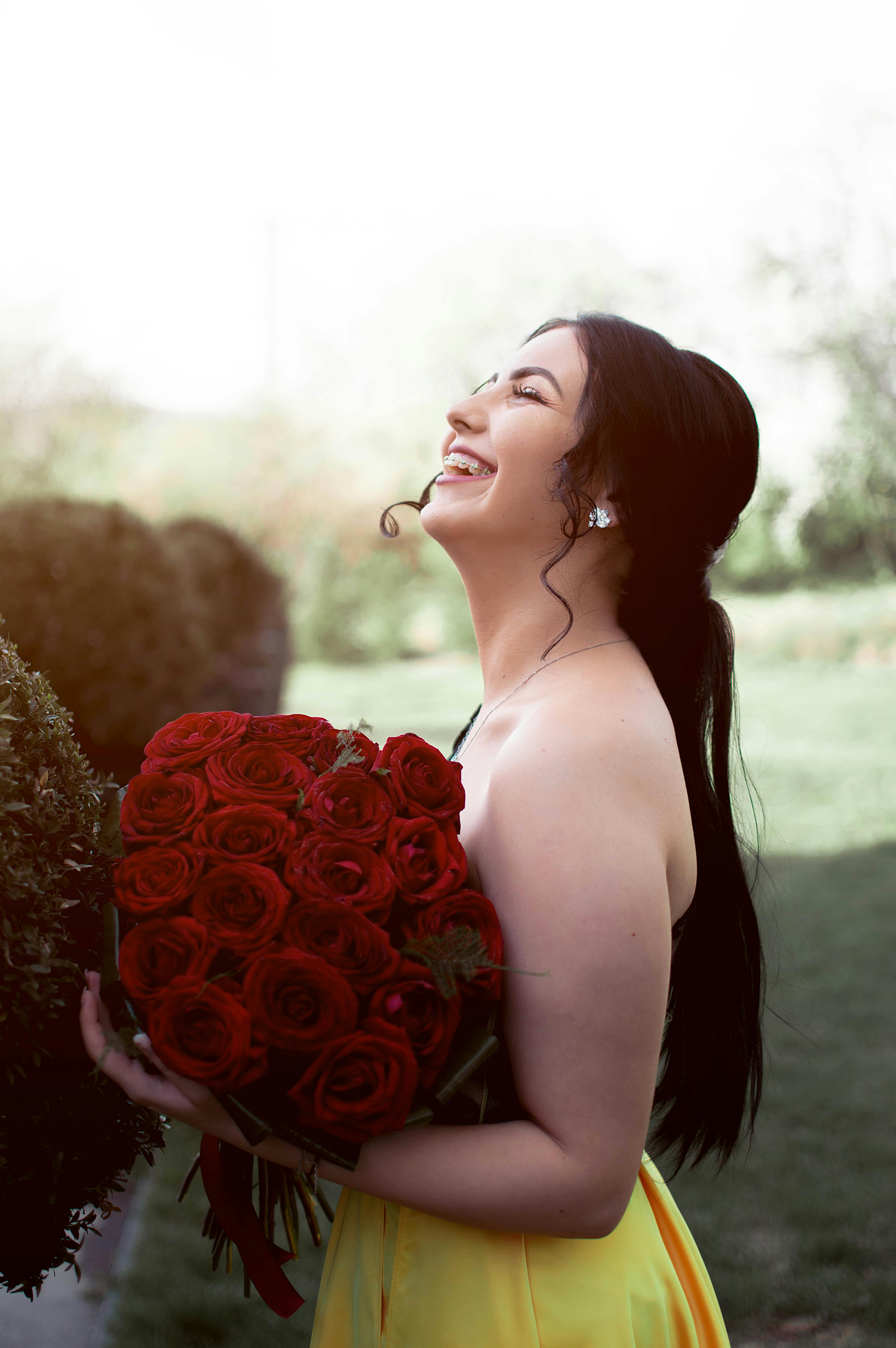 A Laughing Woman Carrying a Bouquet of Red Roses · Free Stock Photo